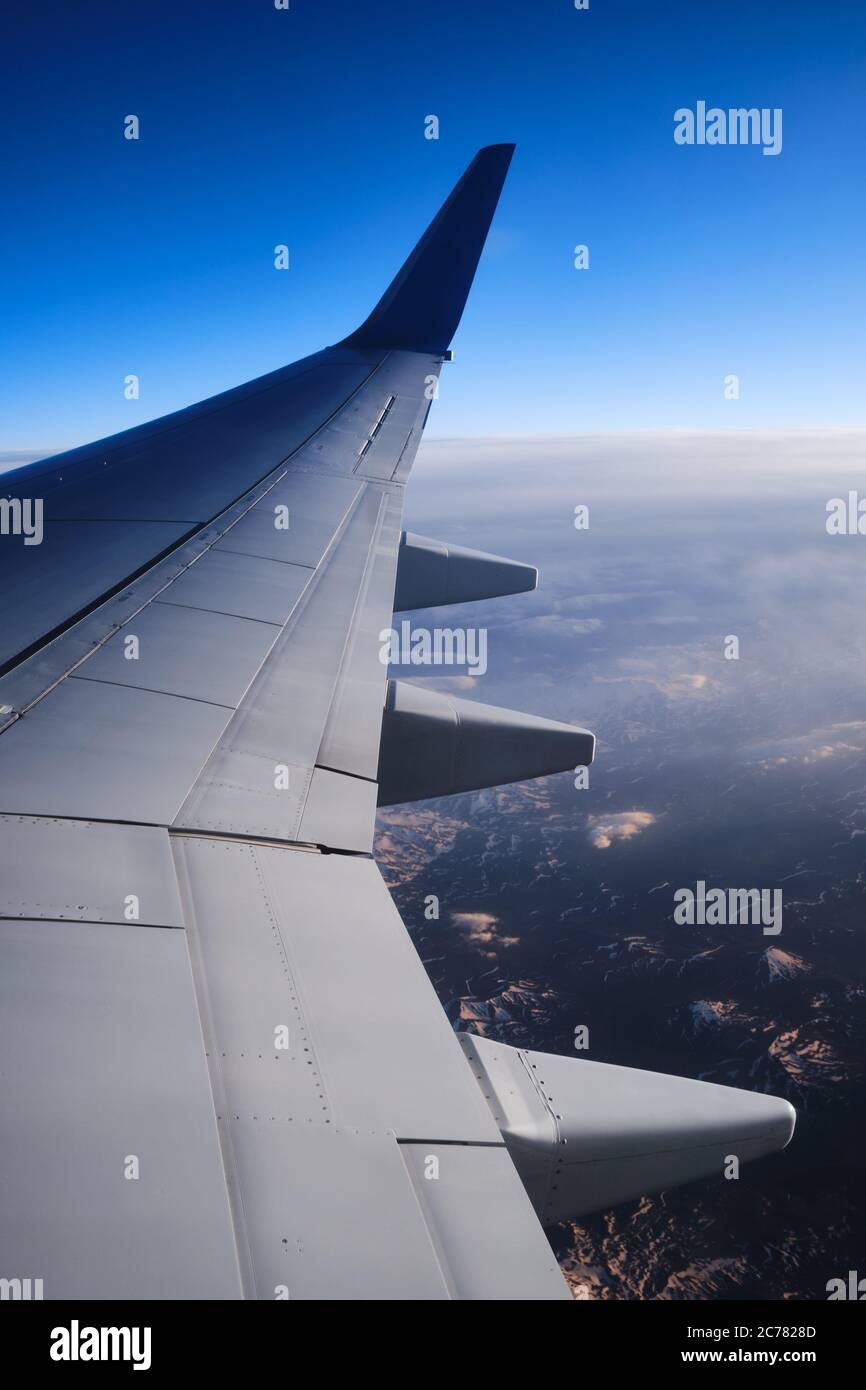 Airplane wing above mountains at sunset vertical view Stock Photo - Alamy