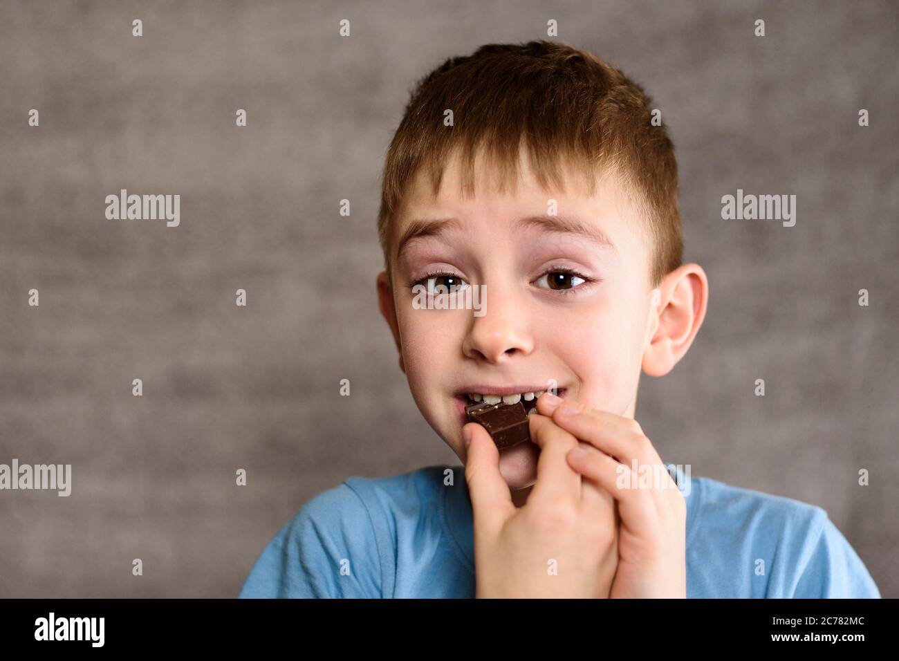 Smiling boy eating a piece of chocolate. Schoolboy snack Stock Photo ...