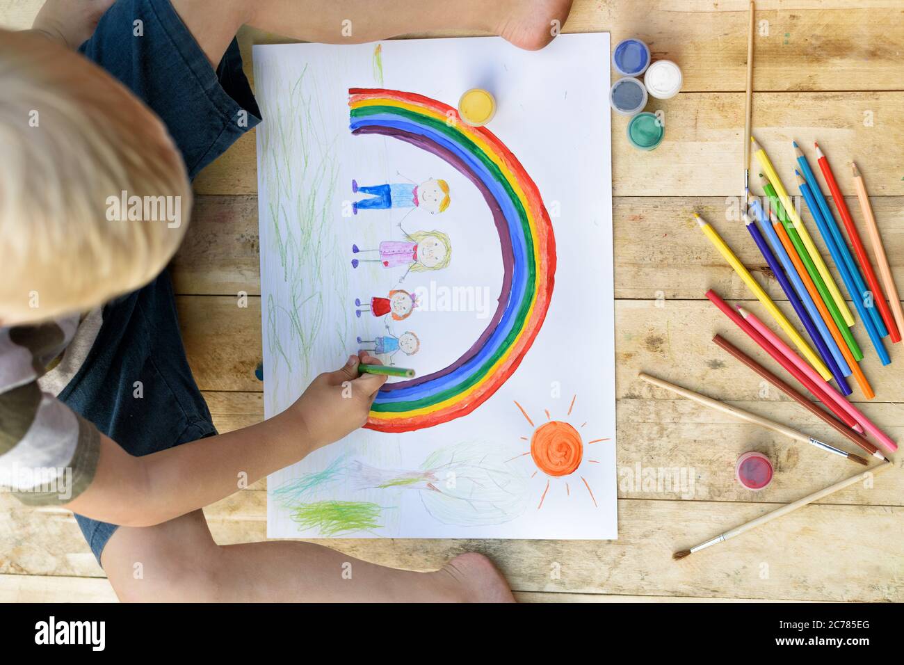 Cute boy draws rainbow and family. Open air. Top view. Creative concept ...