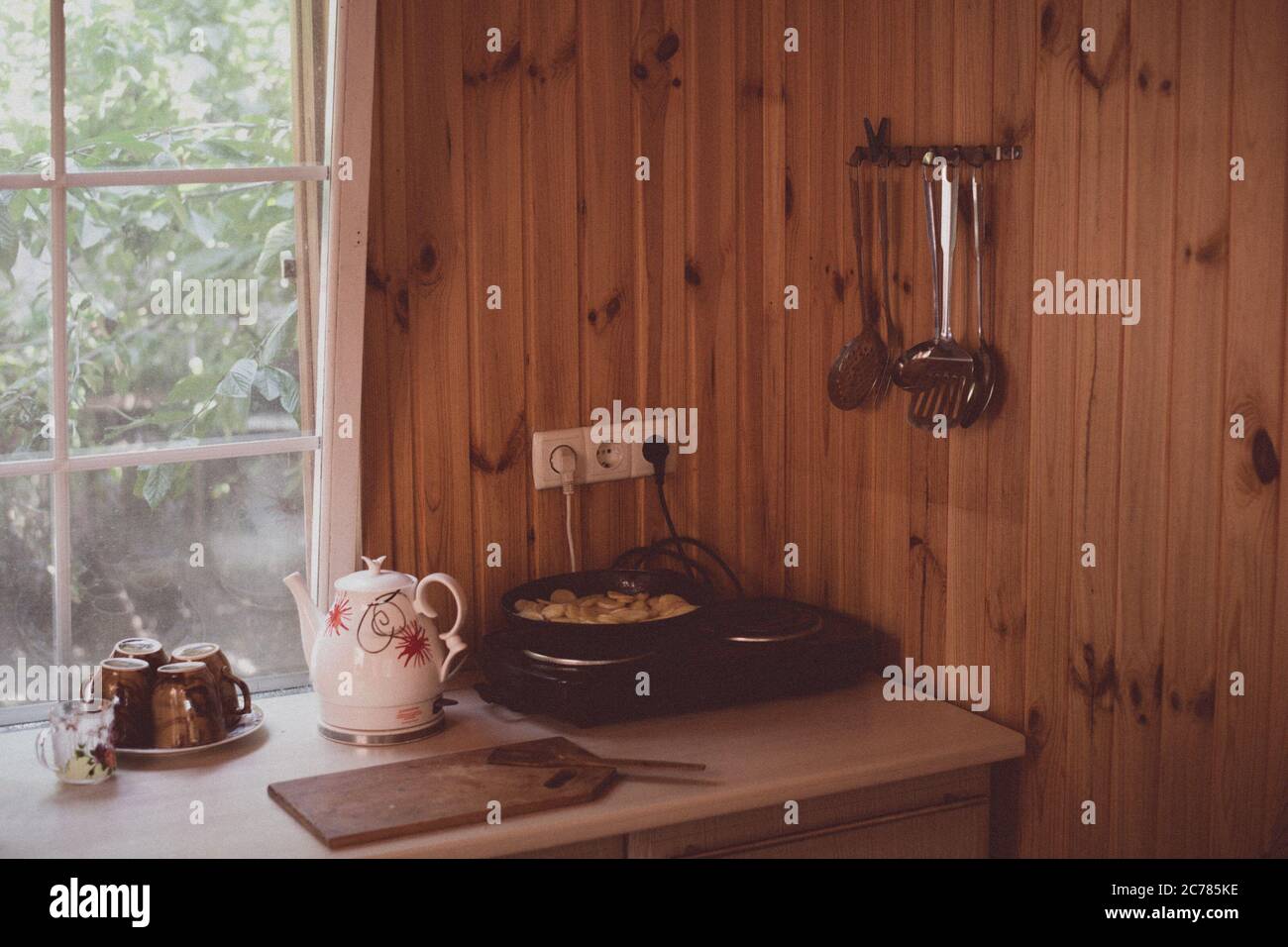Interior of the country kitchen. Frying pan with potatoes on the stove ...