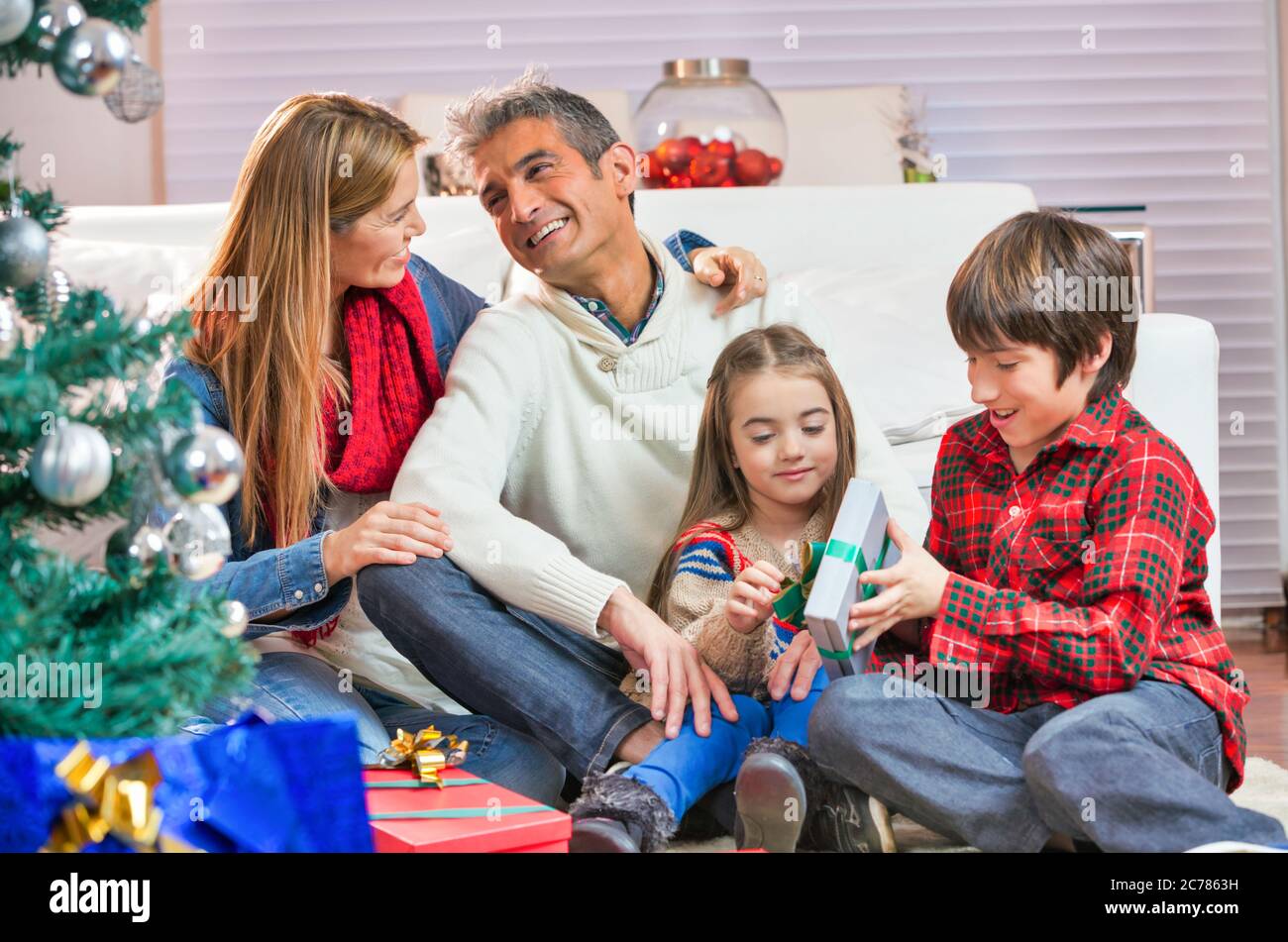 Christmas scene at home. Happy family under the tree Stock Photo - Alamy