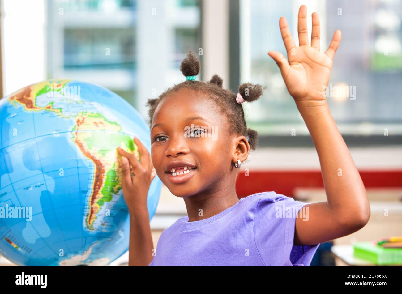 Elementary school scene. African schoolgirl using world globe in the ...