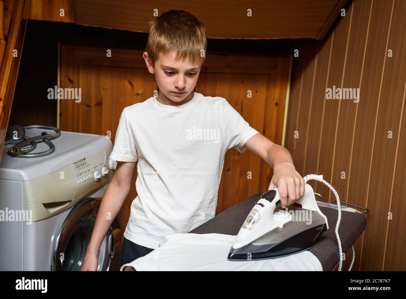 Schoolboy irons his clothes electric iron. Child does homework Stock ...