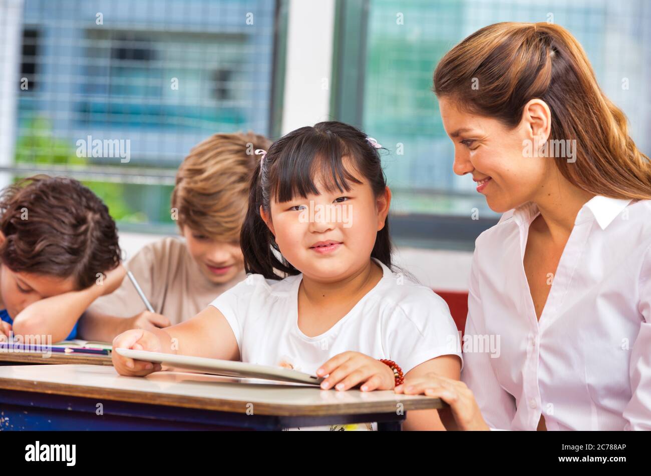 Elementary school scene. Multi ethnic classmates in the classroom ...
