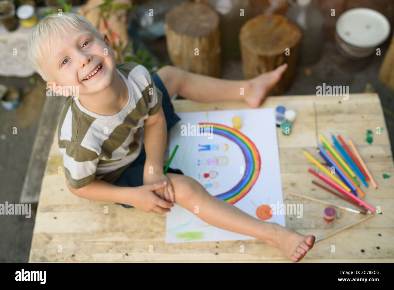 Cute boy draws rainbow and family. Open air. Top view. Creative concept ...