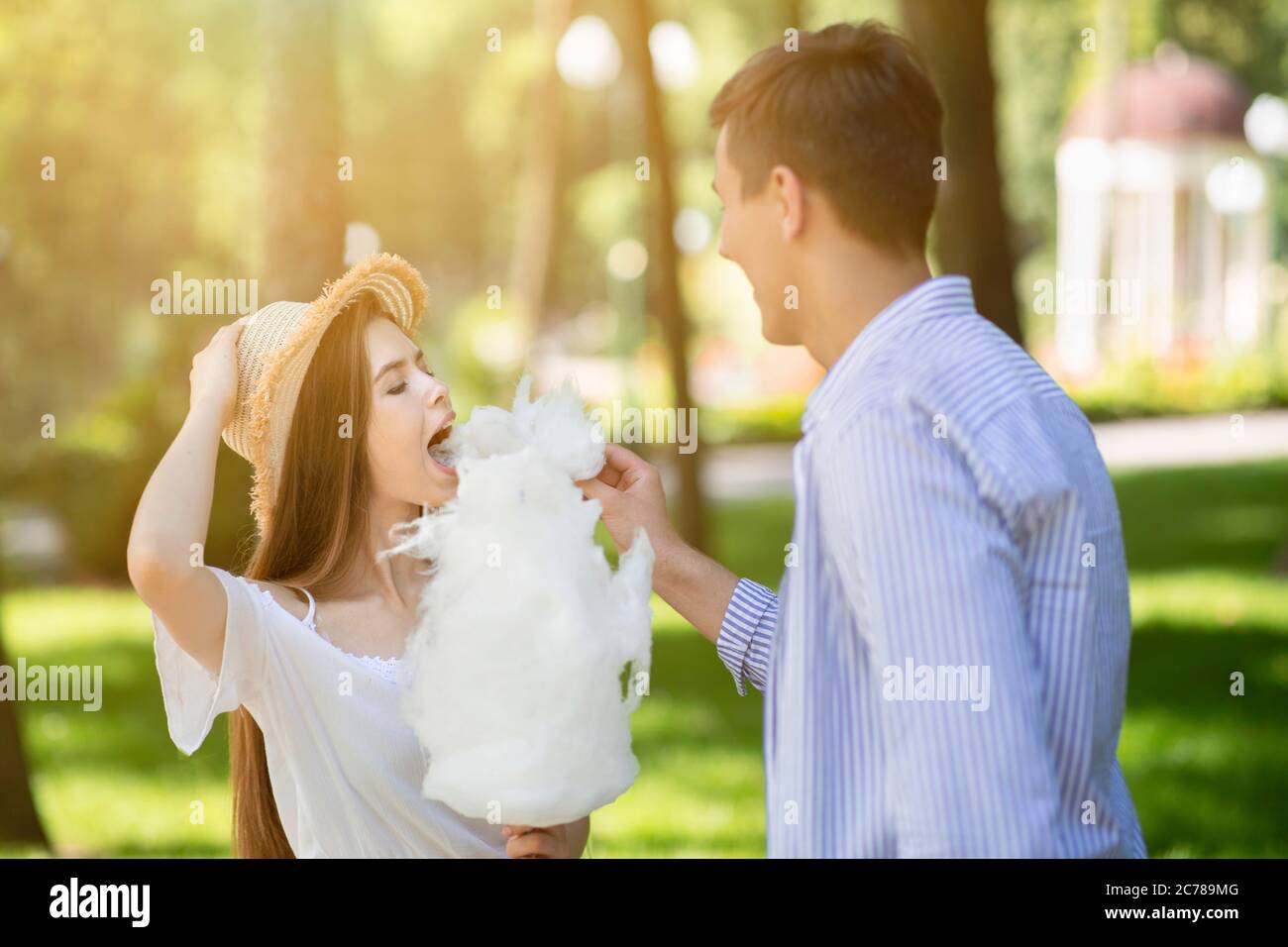 Romantic times together. Happy millennial couple eating candy floss ...