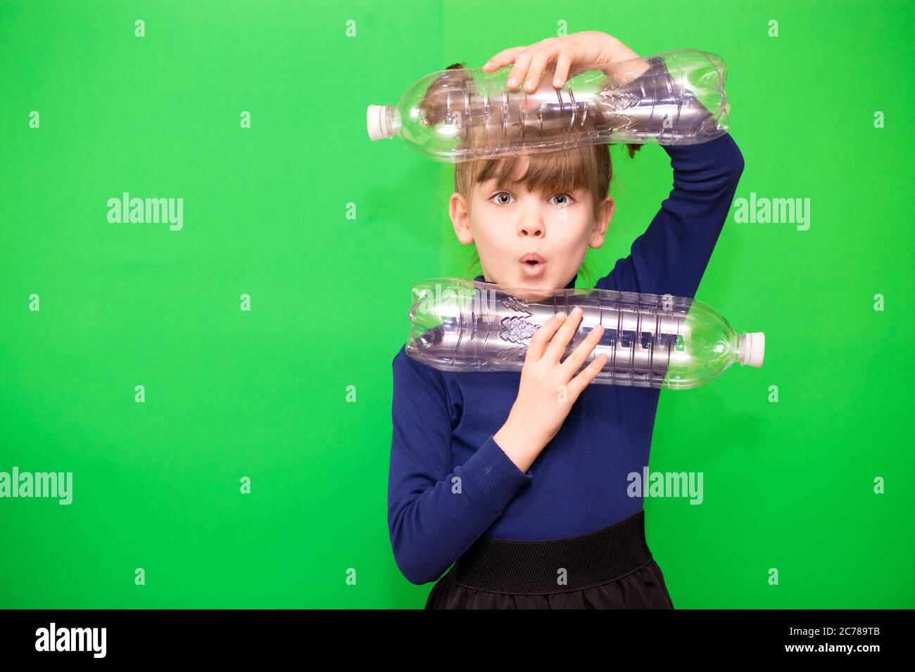 Photo of confused funny little girl holding plastic bottles and looking ...