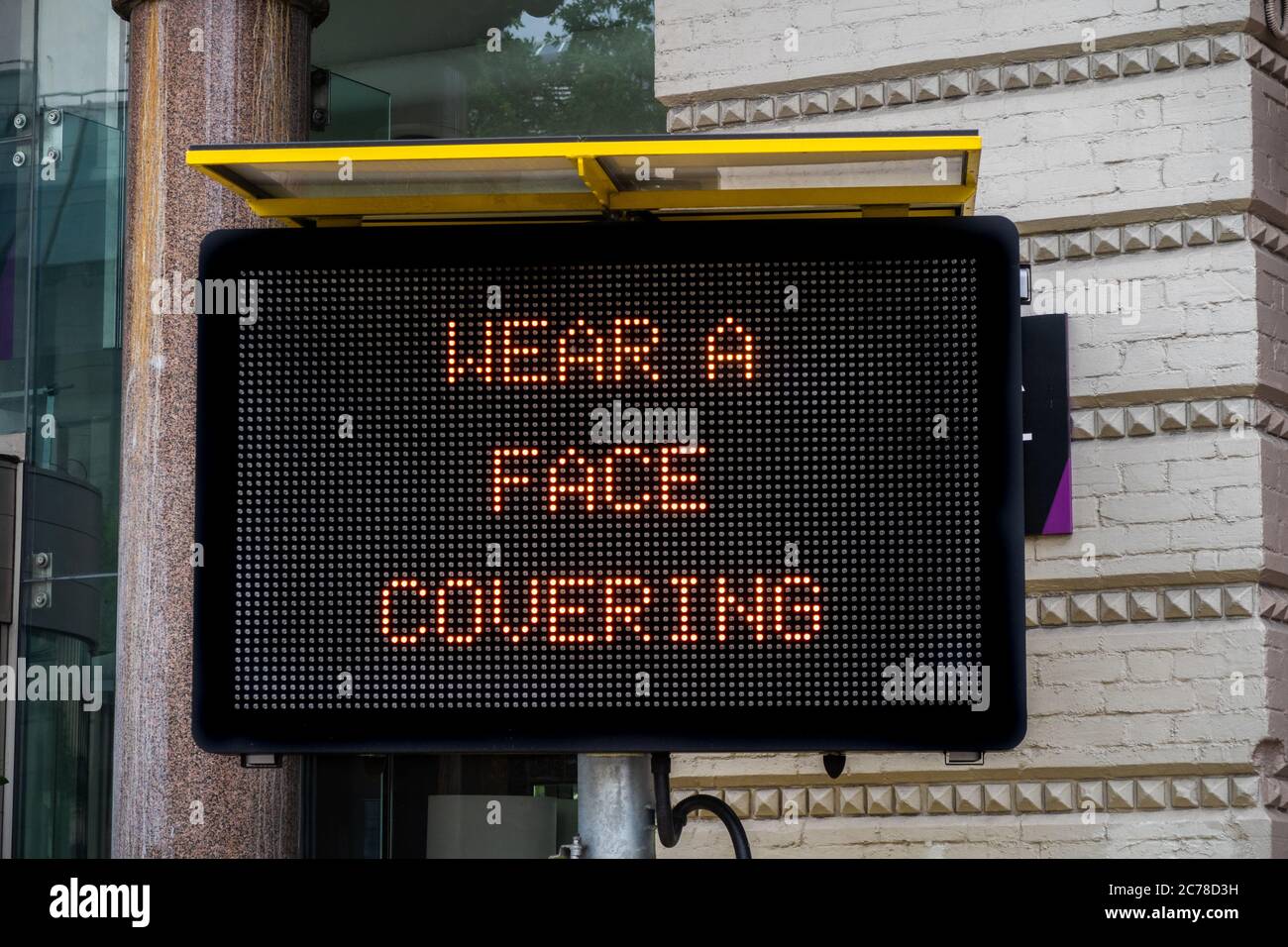 An electronic sign instructing people to wear a face covering. Seen ...