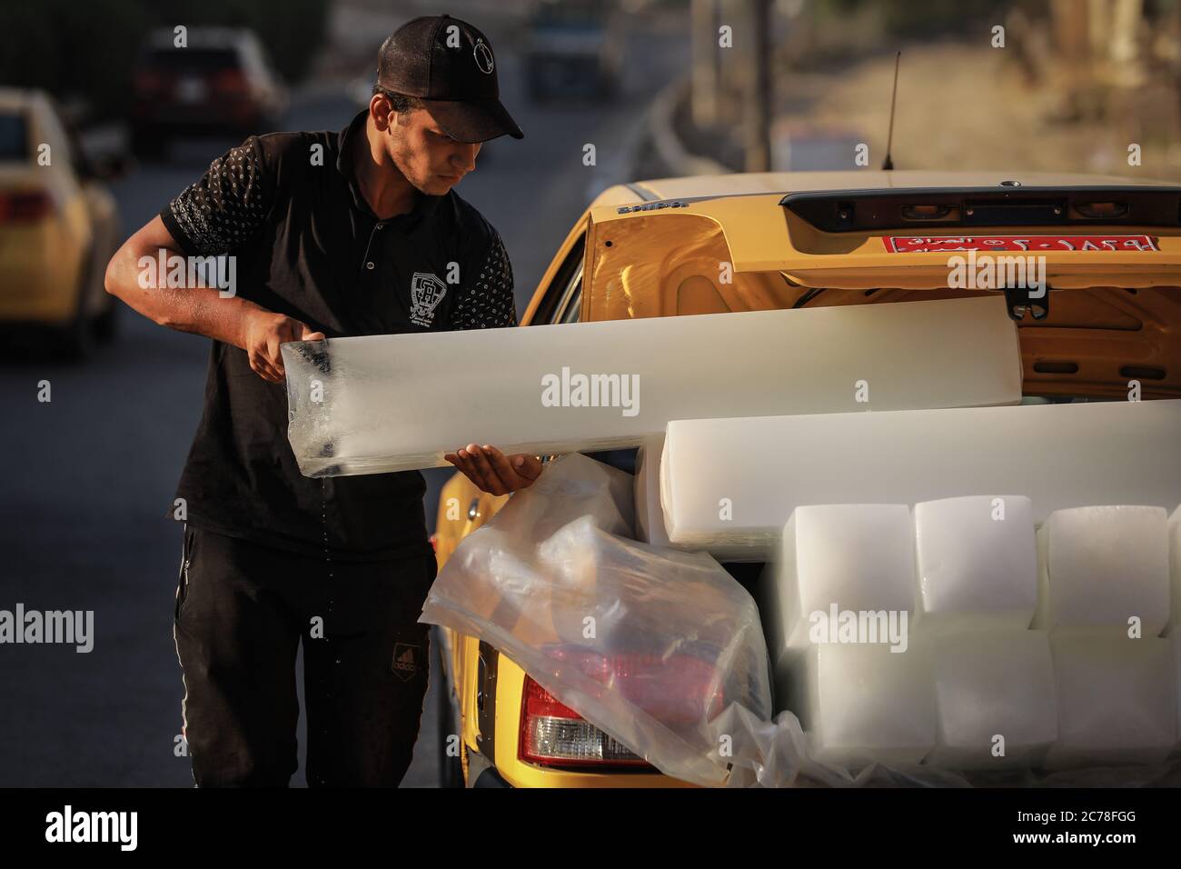 Baghdad, Iraq. 15th July, 2020. A man puts ice blocks in a car trunk ...
