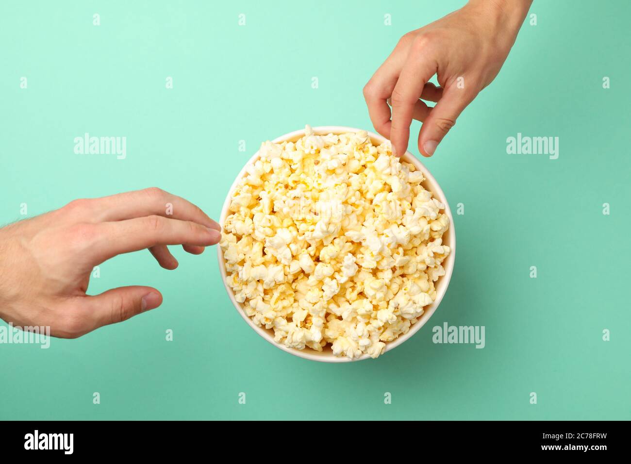 Men's hands take popcorn from a bucket on mint background Stock Photo ...