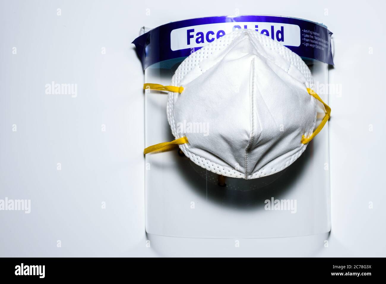 A face mask covered on a face shield placed on a white surface. To use ...