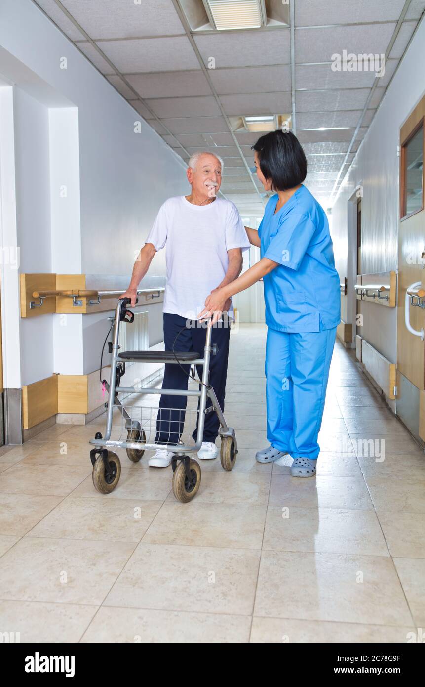 Asian nurse assisting elderly man with walker walking on the hospital ...