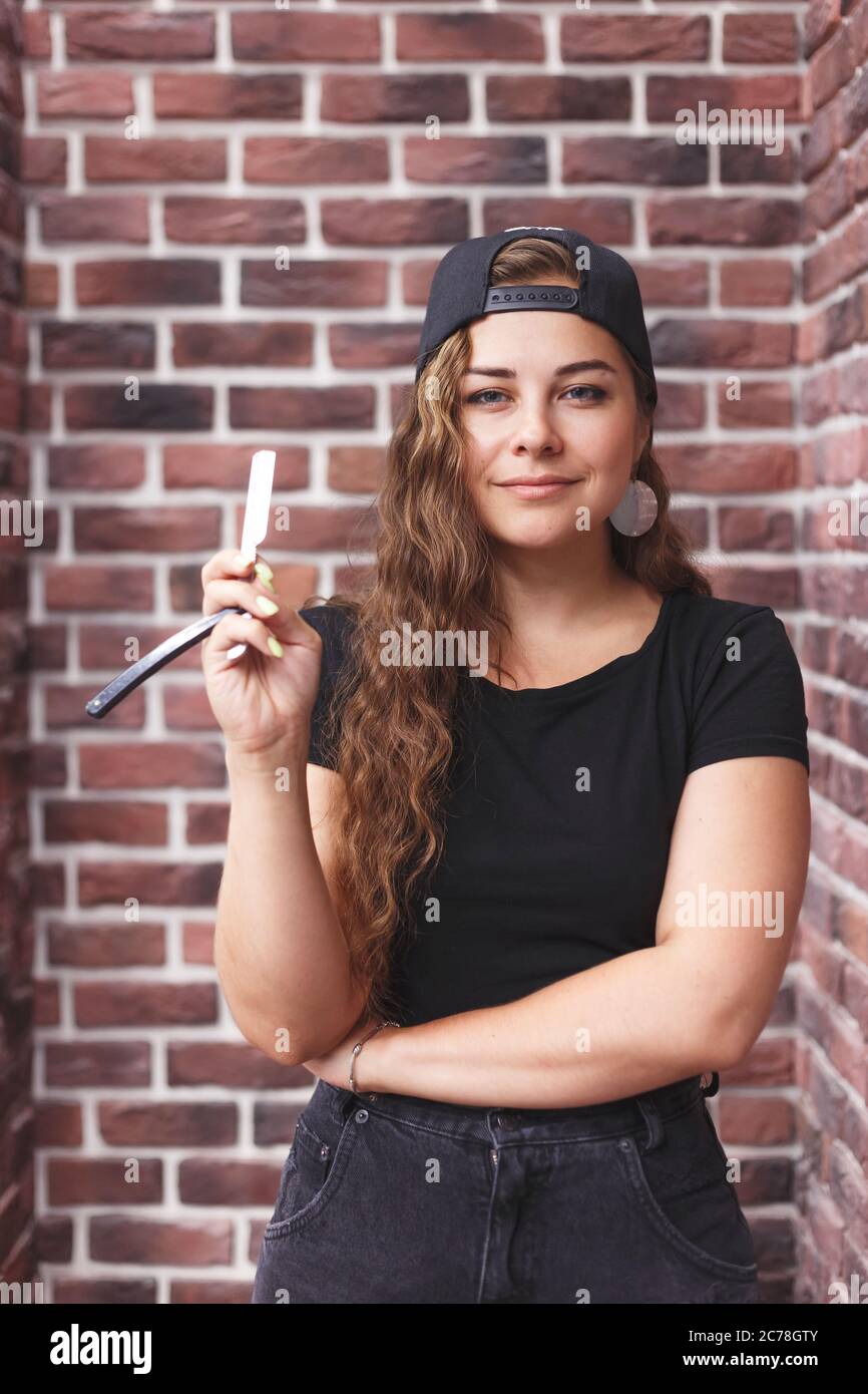 Young caucasian professional barber woman holding a straight razor ...
