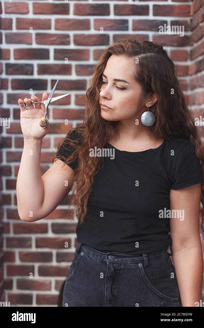 Young caucasian barber woman holding a straight razor and scissors ...