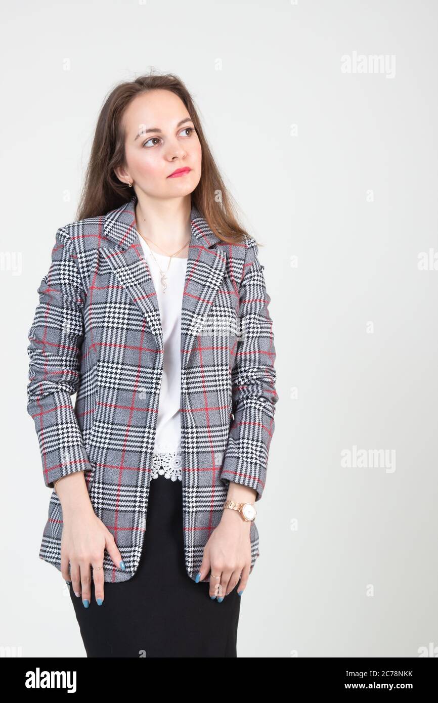 beautiful young woman in business strict clothes poses against a white ...