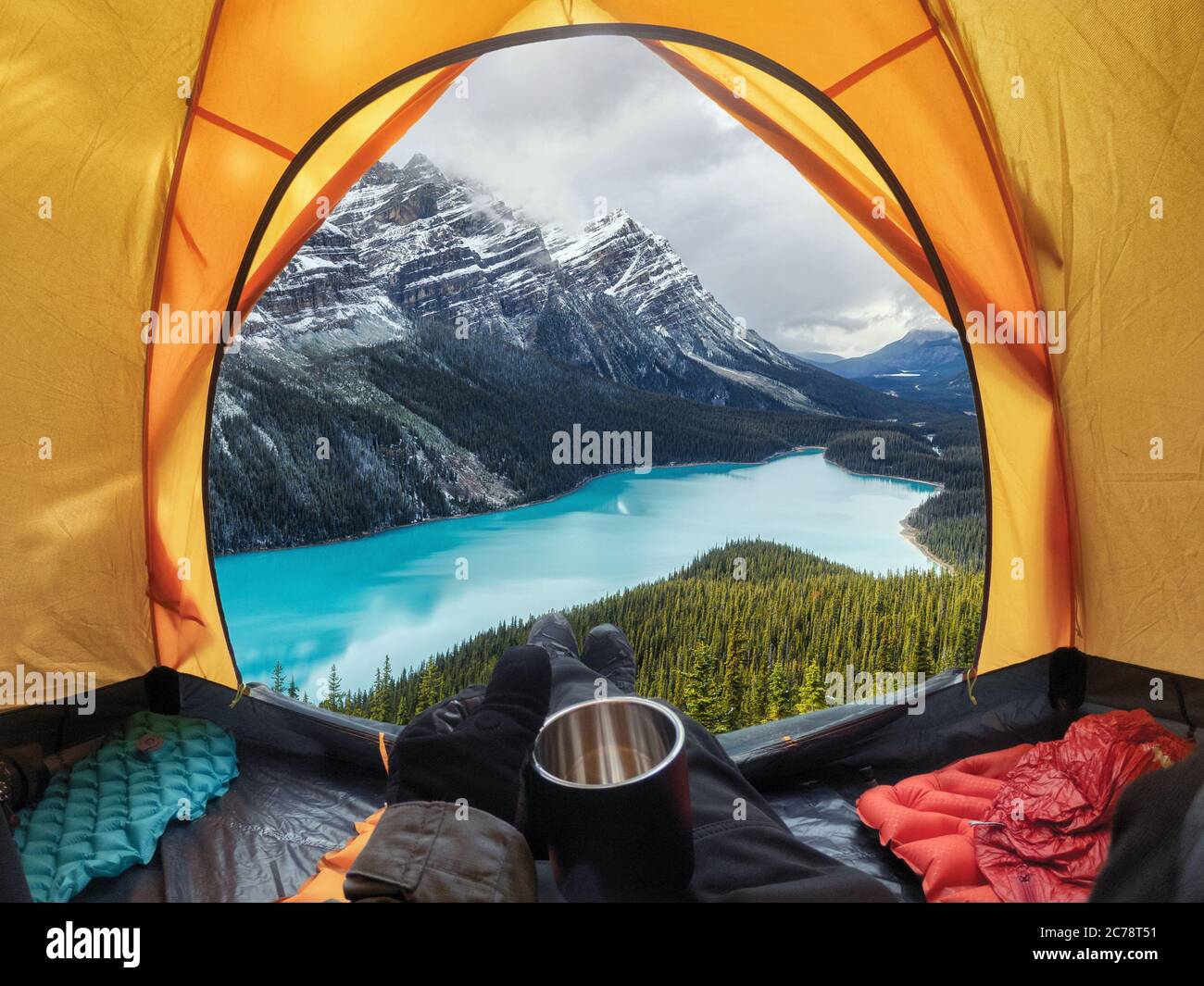 Camping with holding cup in yellow tent open with Peyto Lake in ...