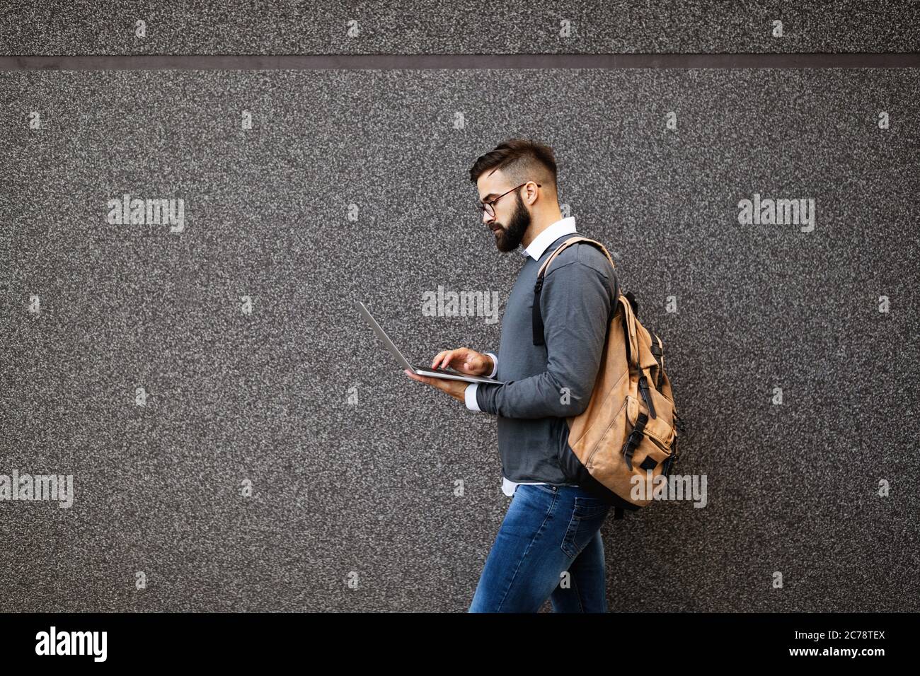 Businessman walking in street holding his laptop, working outdoor Stock ...