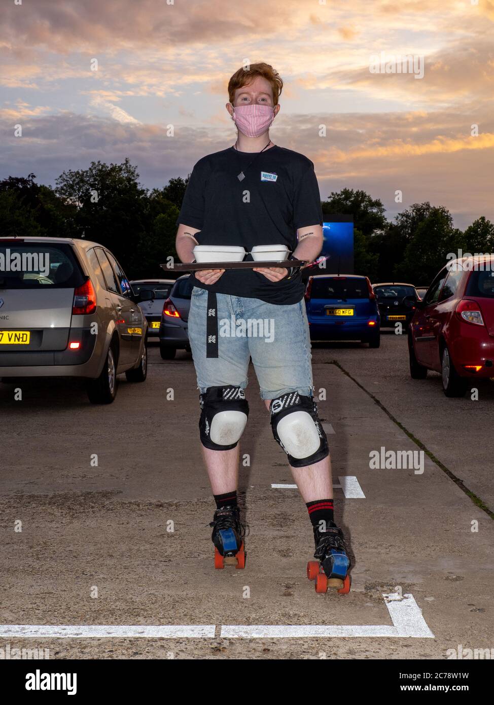 A waiter on roller skates serving guests at the drive in screening of ...