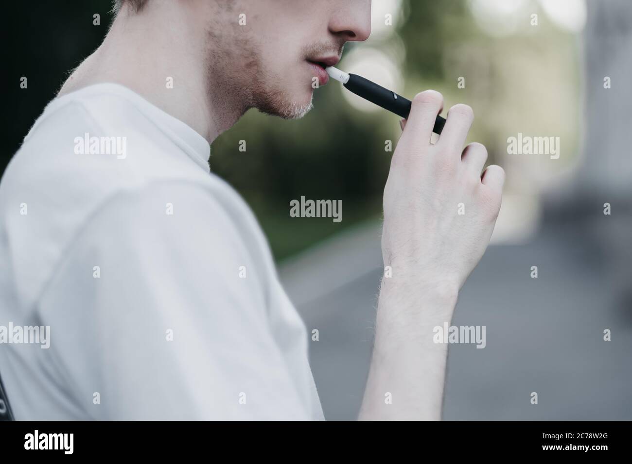 A young man in nature smoking IQOS Stock Photo - Alamy