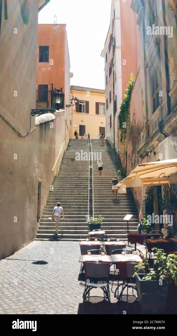 Sidewalk cafe in Rome, Italy. Outdoor cafe in alley. People walking up ...
