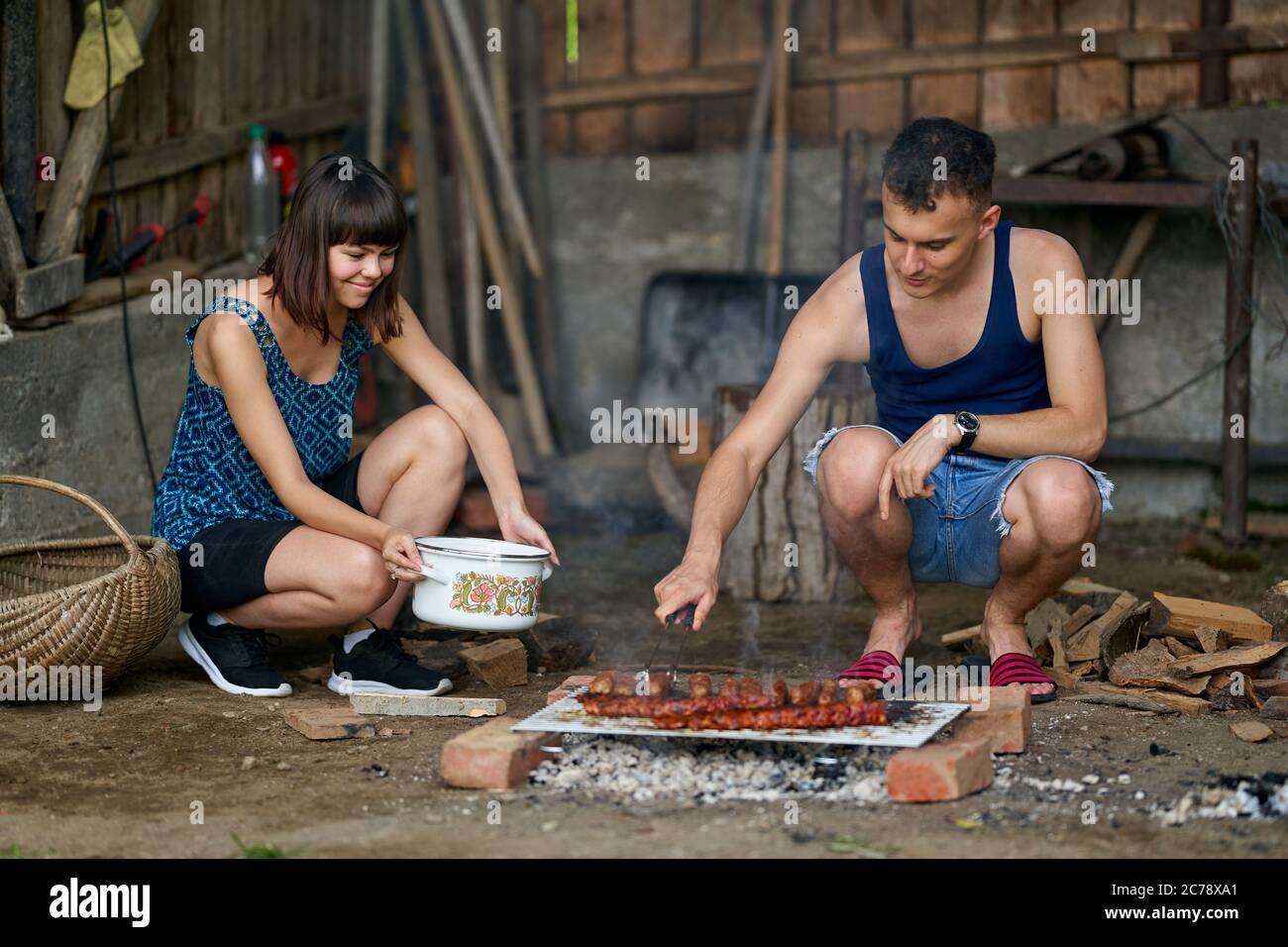 Happy young couple making a barbecue in the countryside Stock Photo - Alamy