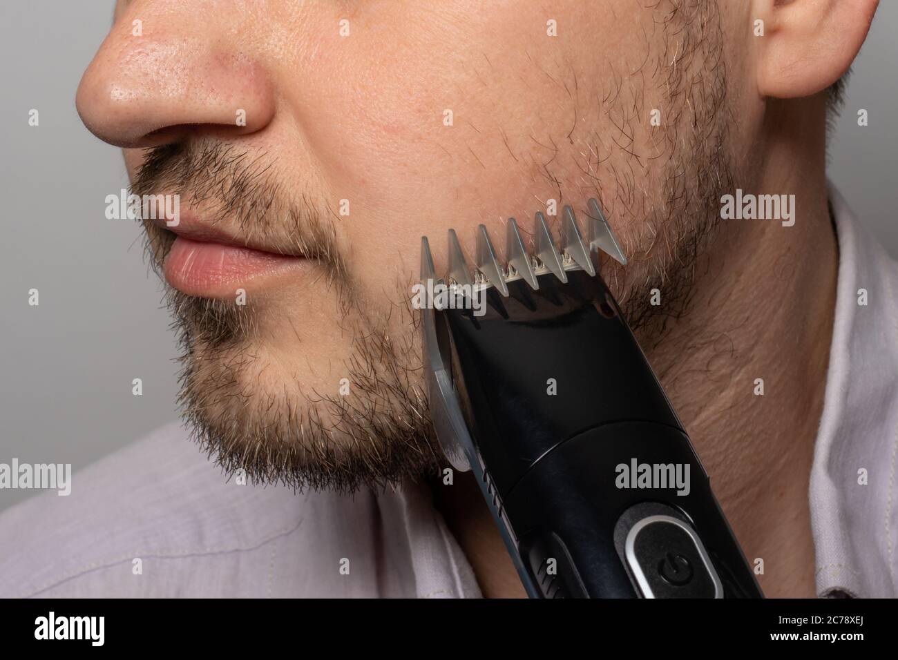 A man shaves his beard with a trimmer razor. Modeling beard, masculine ...