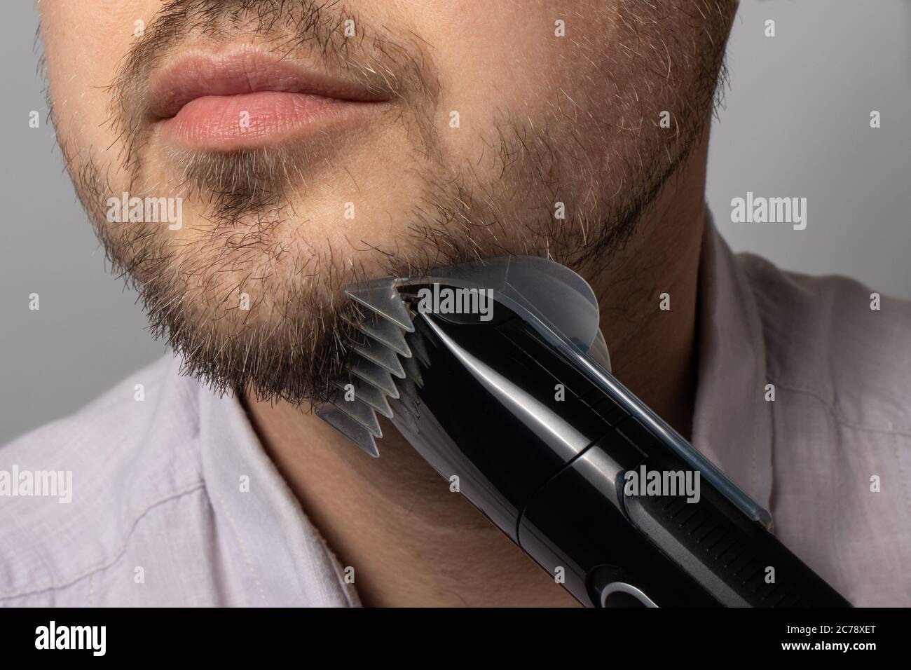 A man shaves his beard with a trimmer razor. Modeling beard, masculine ...