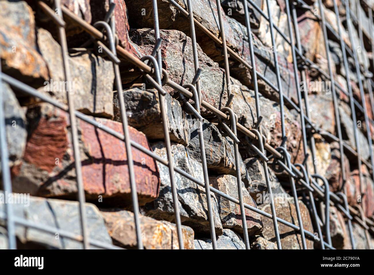Background made of a stone wall secured with a galvanized metal mesh ...