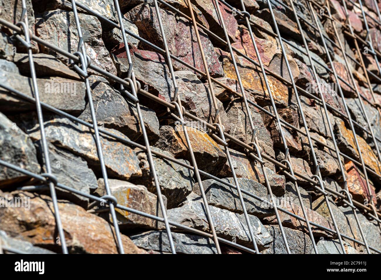 Background made of a stone wall secured with a galvanized metal mesh ...