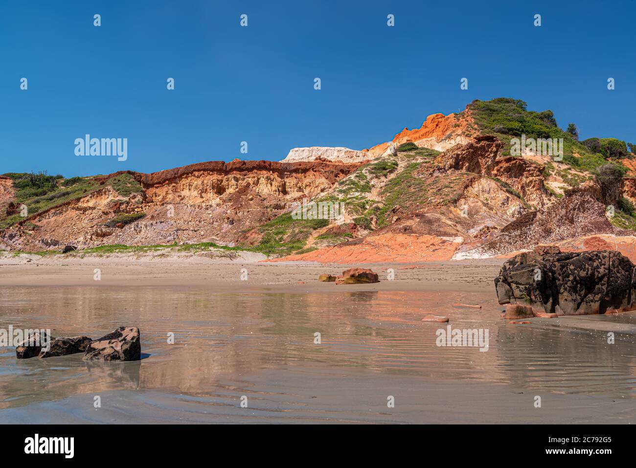 Colored stones and sand on the beach, in the background cliffs with ...