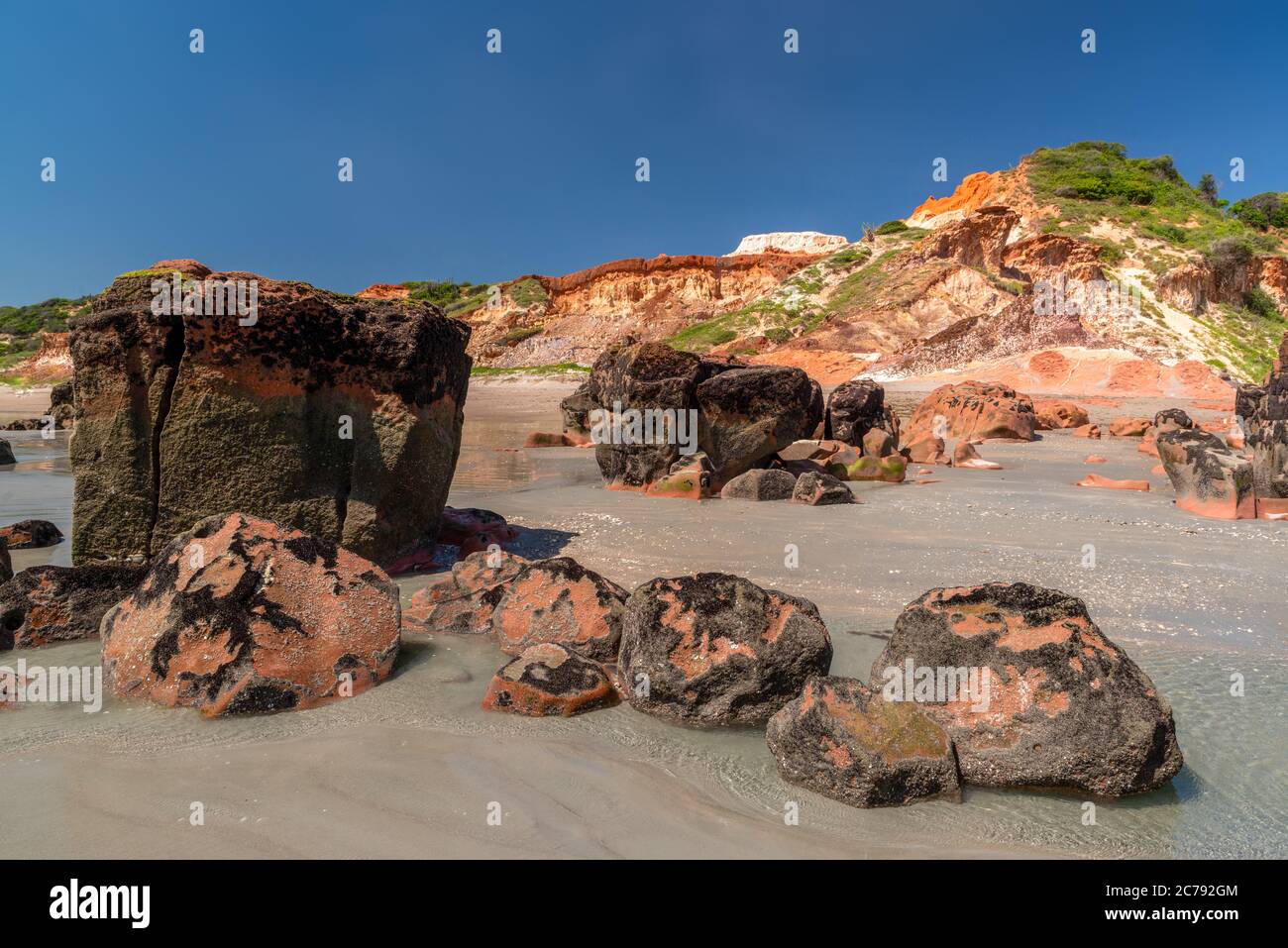 Colored stones and sand on the beach, in the background cliffs with ...