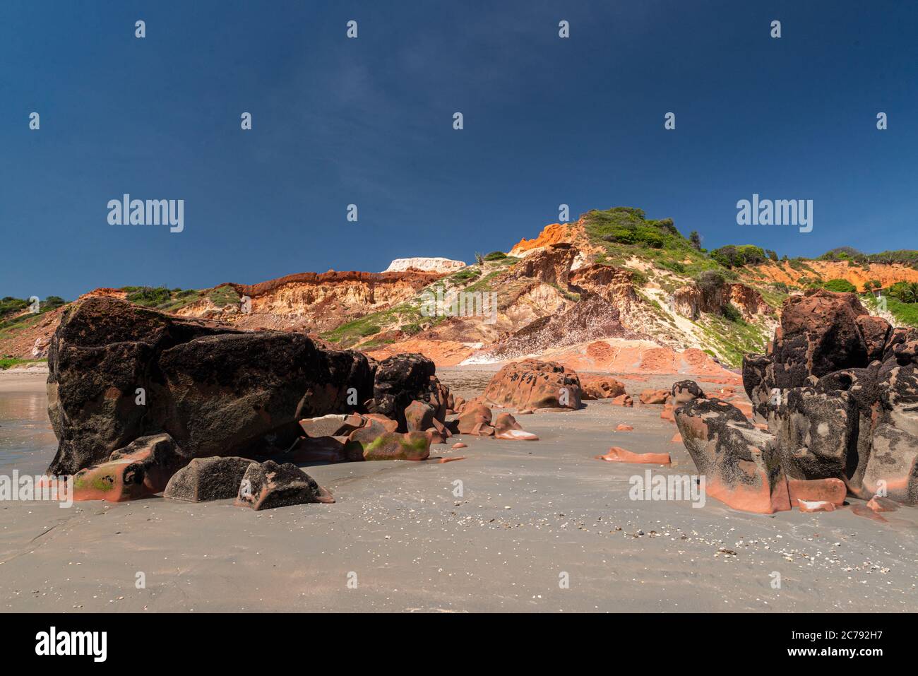 Colored stones and sand on the beach, in the background cliffs with ...