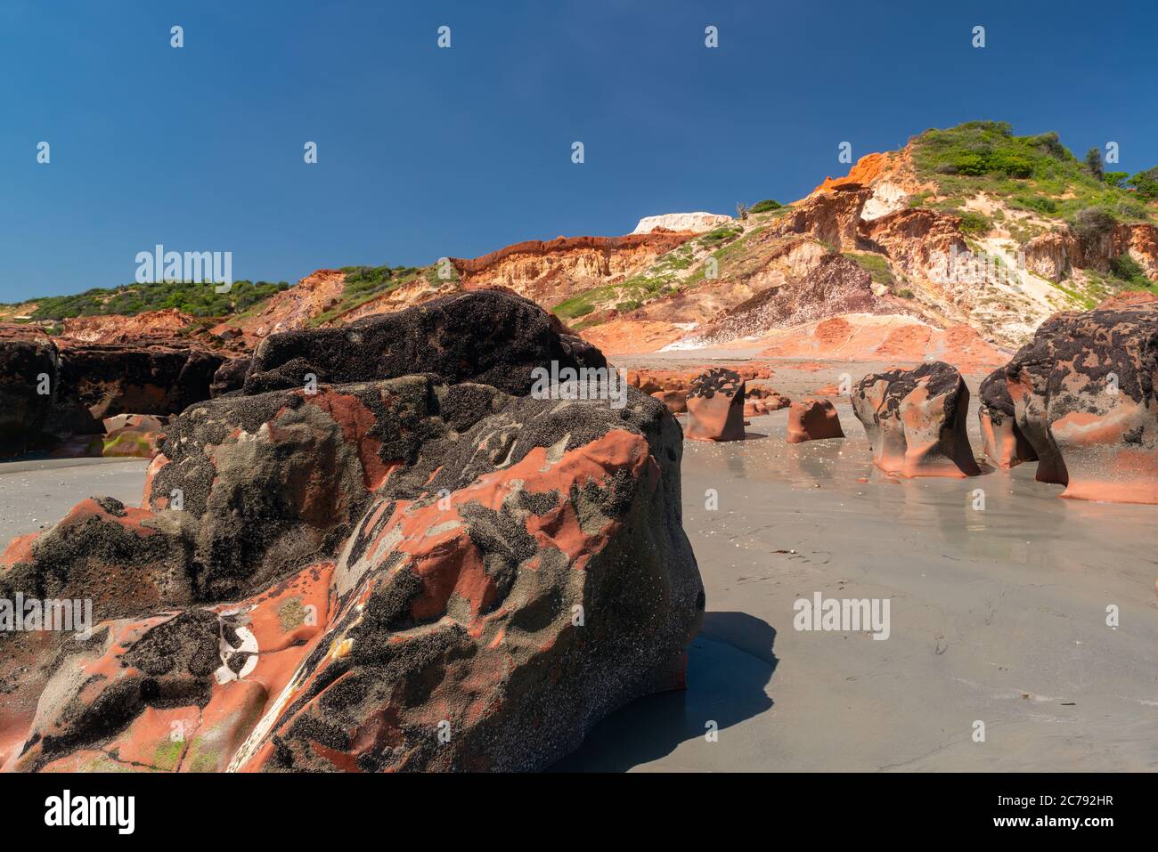 Colored stones and sand on the beach, in the background cliffs with ...