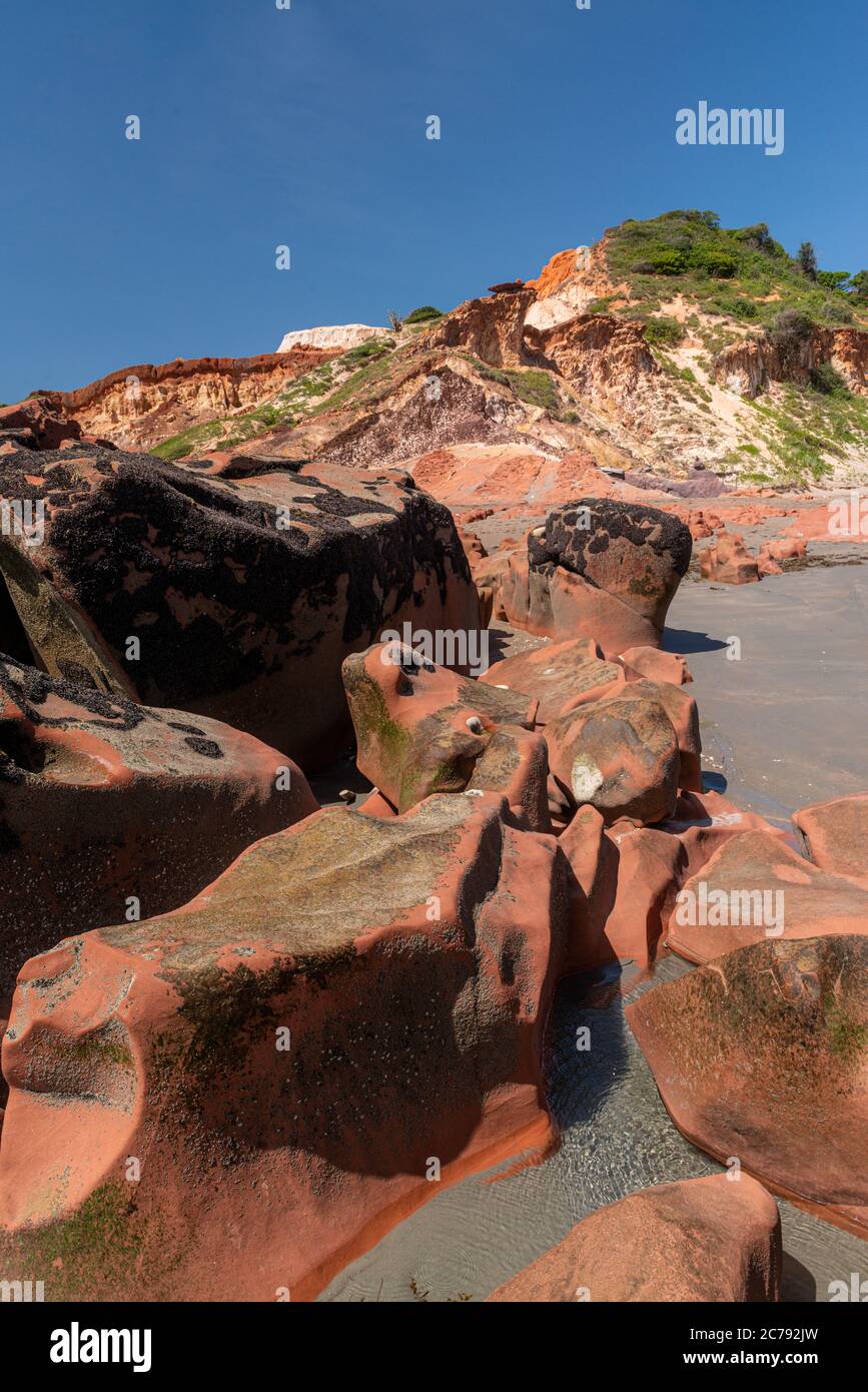 Colored stones and sand on the beach, in the background cliffs with ...