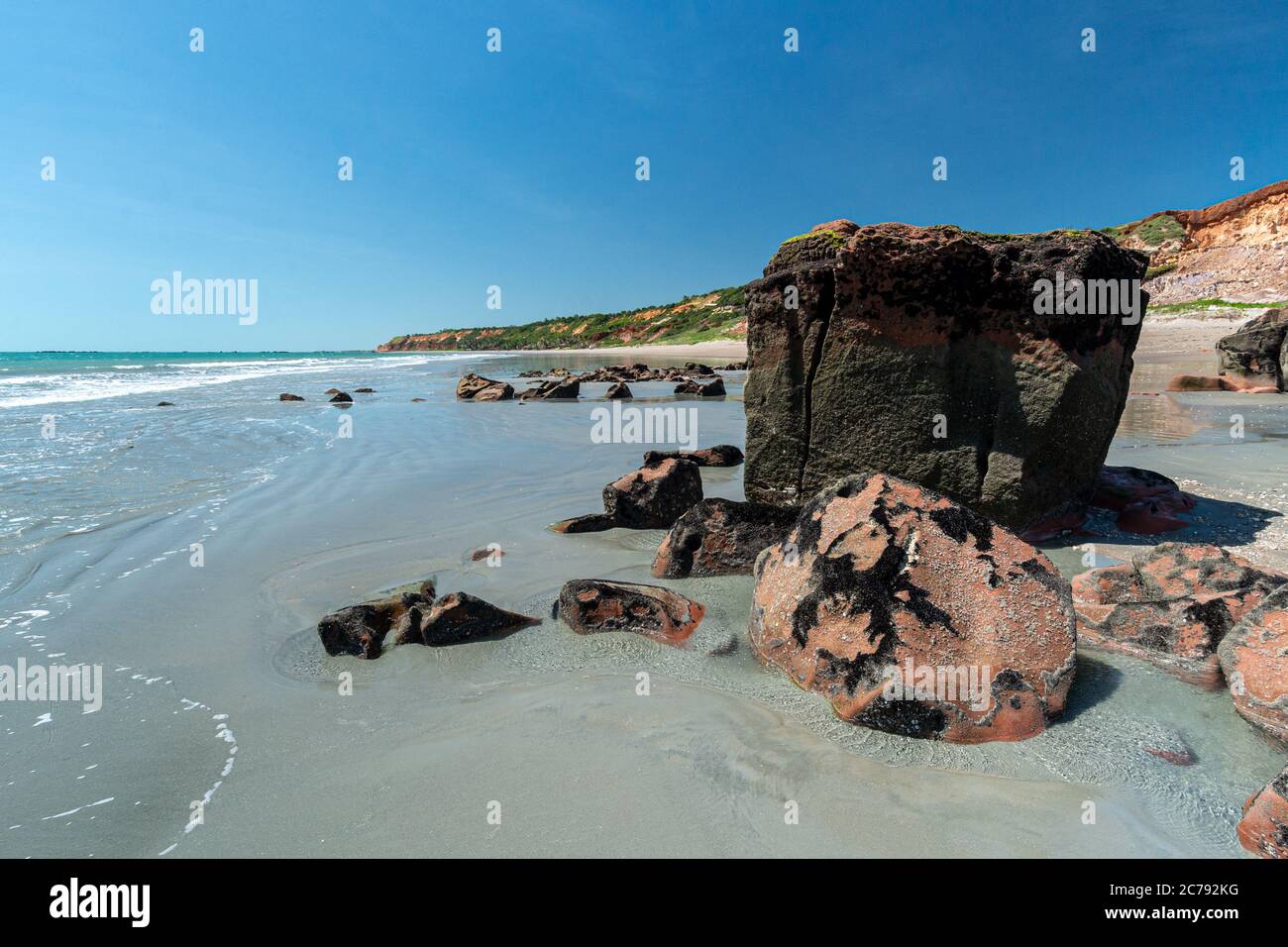 Colored stones and sand on the beach, in the background cliffs with ...