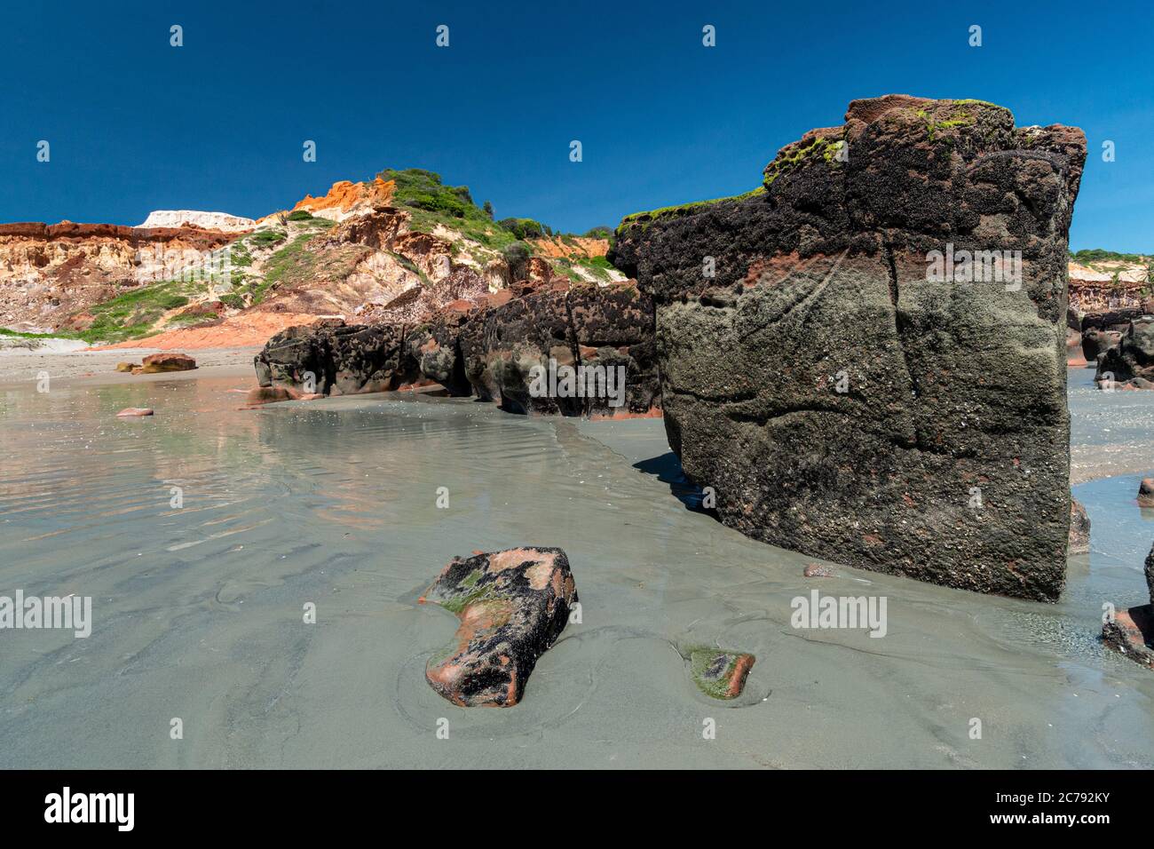 Colored stones and sand on the beach, in the background cliffs with ...