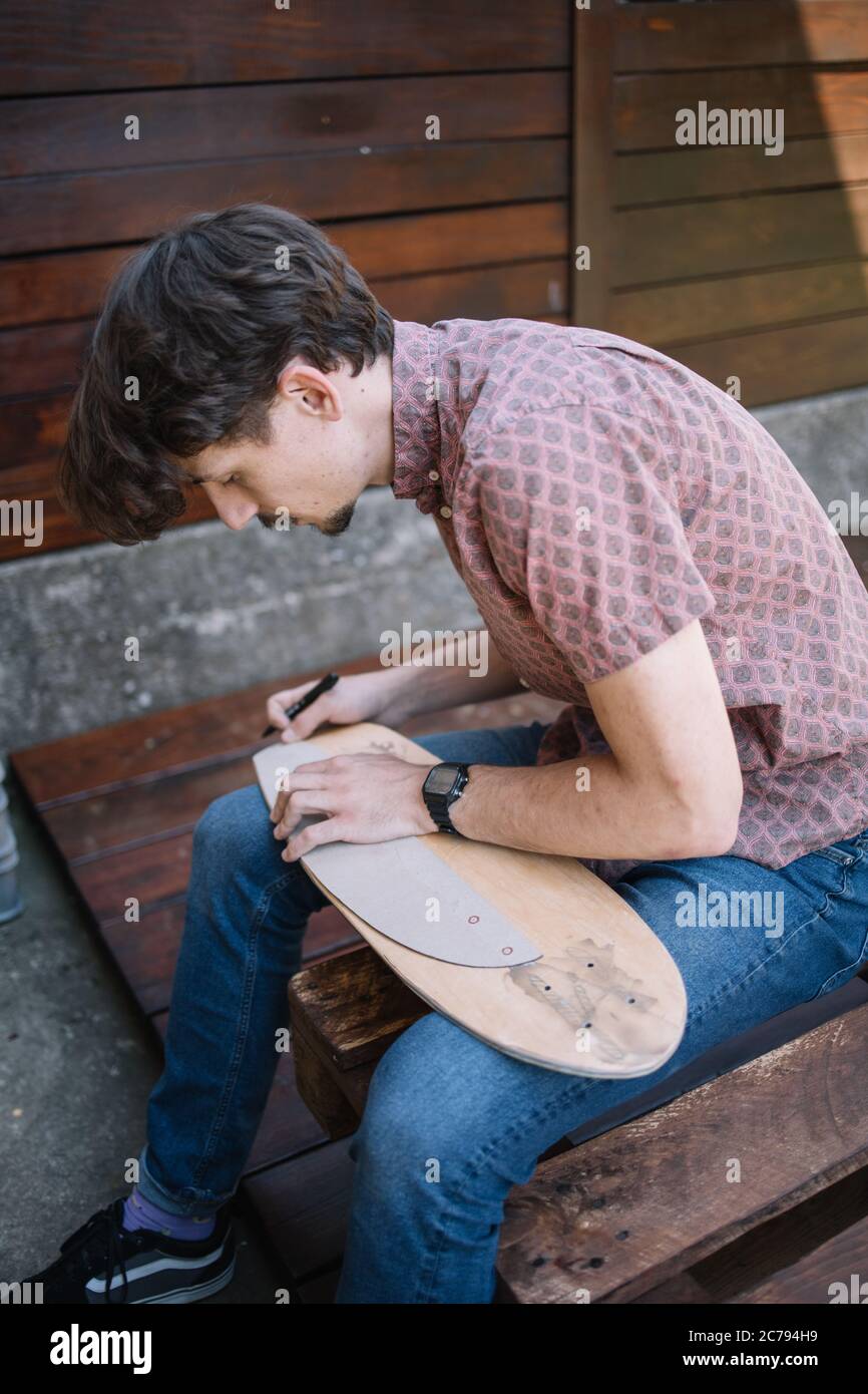 Side view of man marking template on skateboard Stock Photo - Alamy