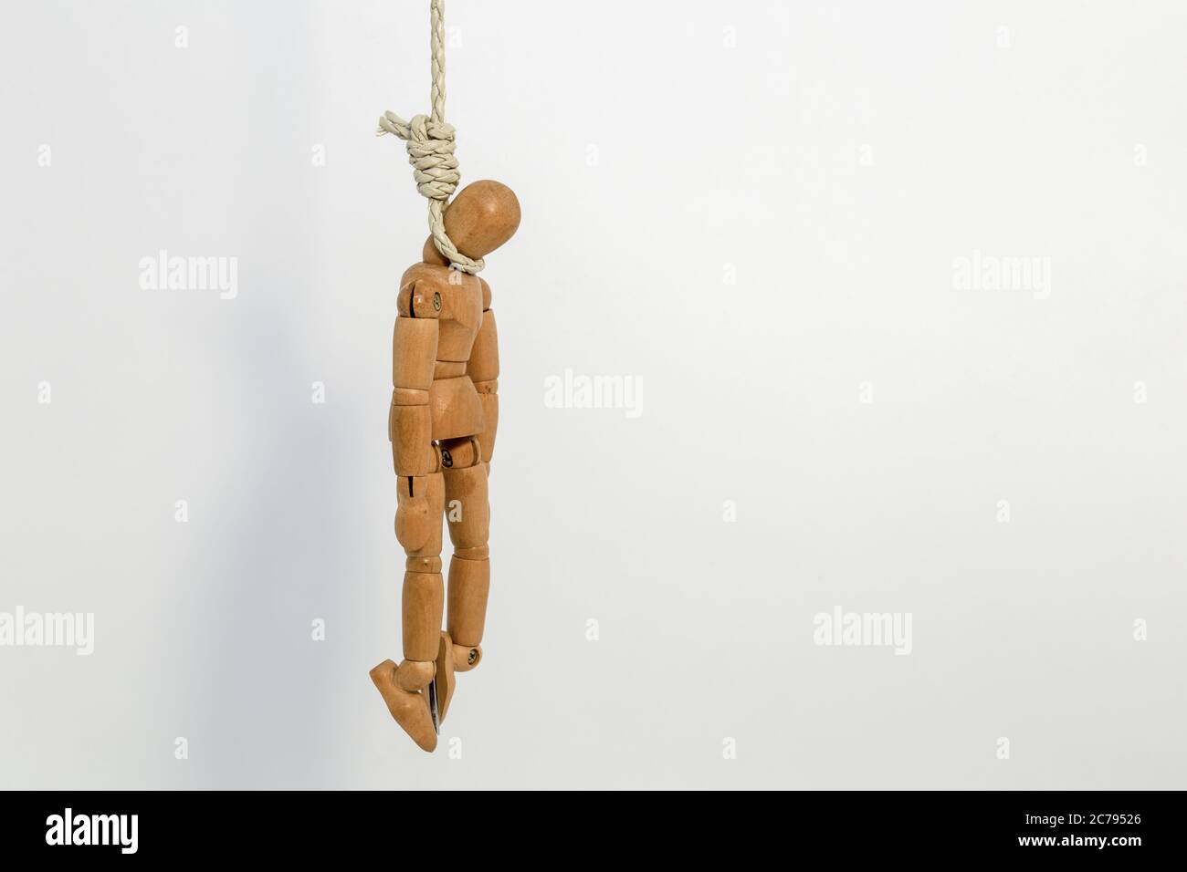 A wooden drawing mannequin hanging from a rope, over white background ...