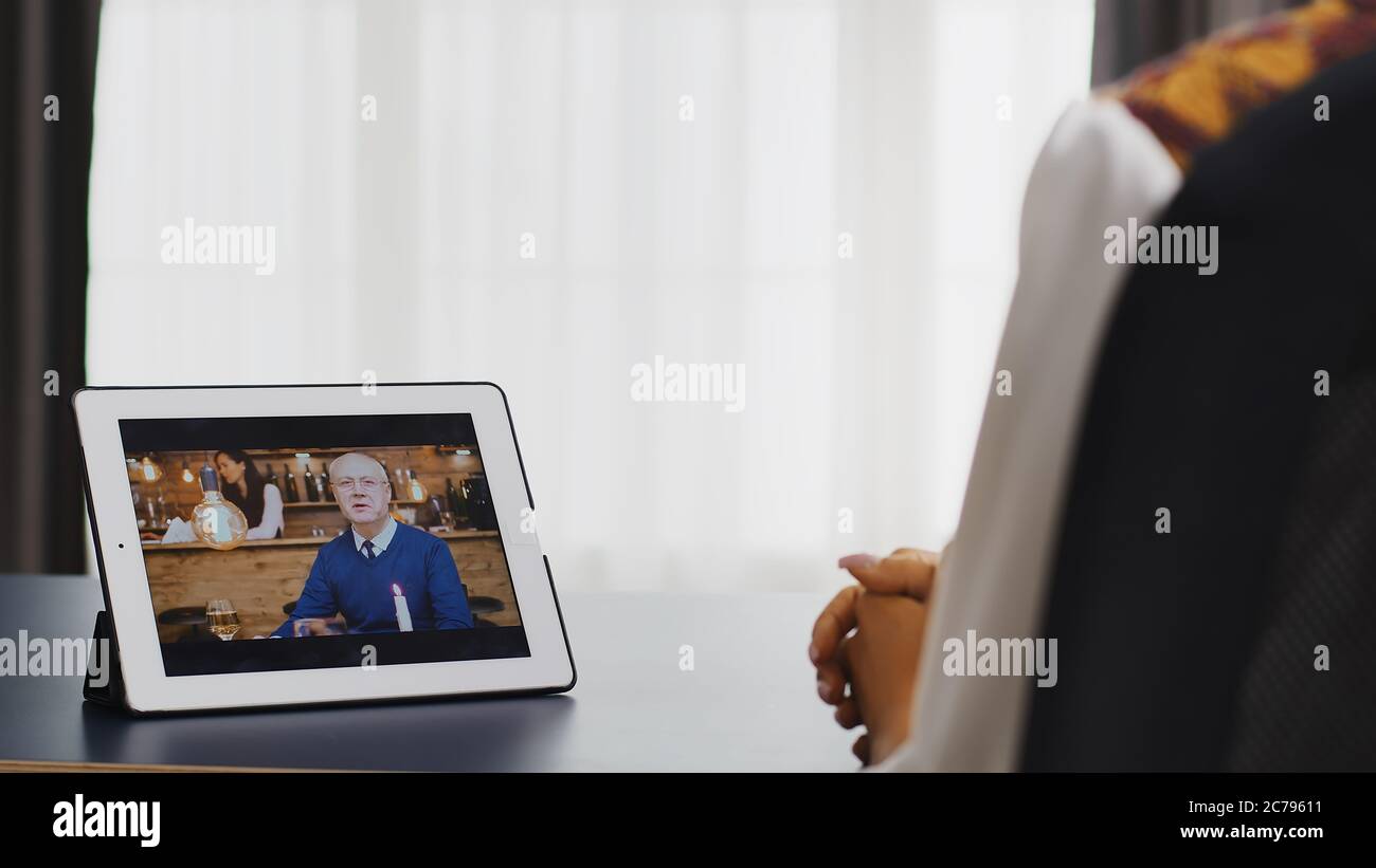 Happy woman talking with her father on a video call using tablet ...