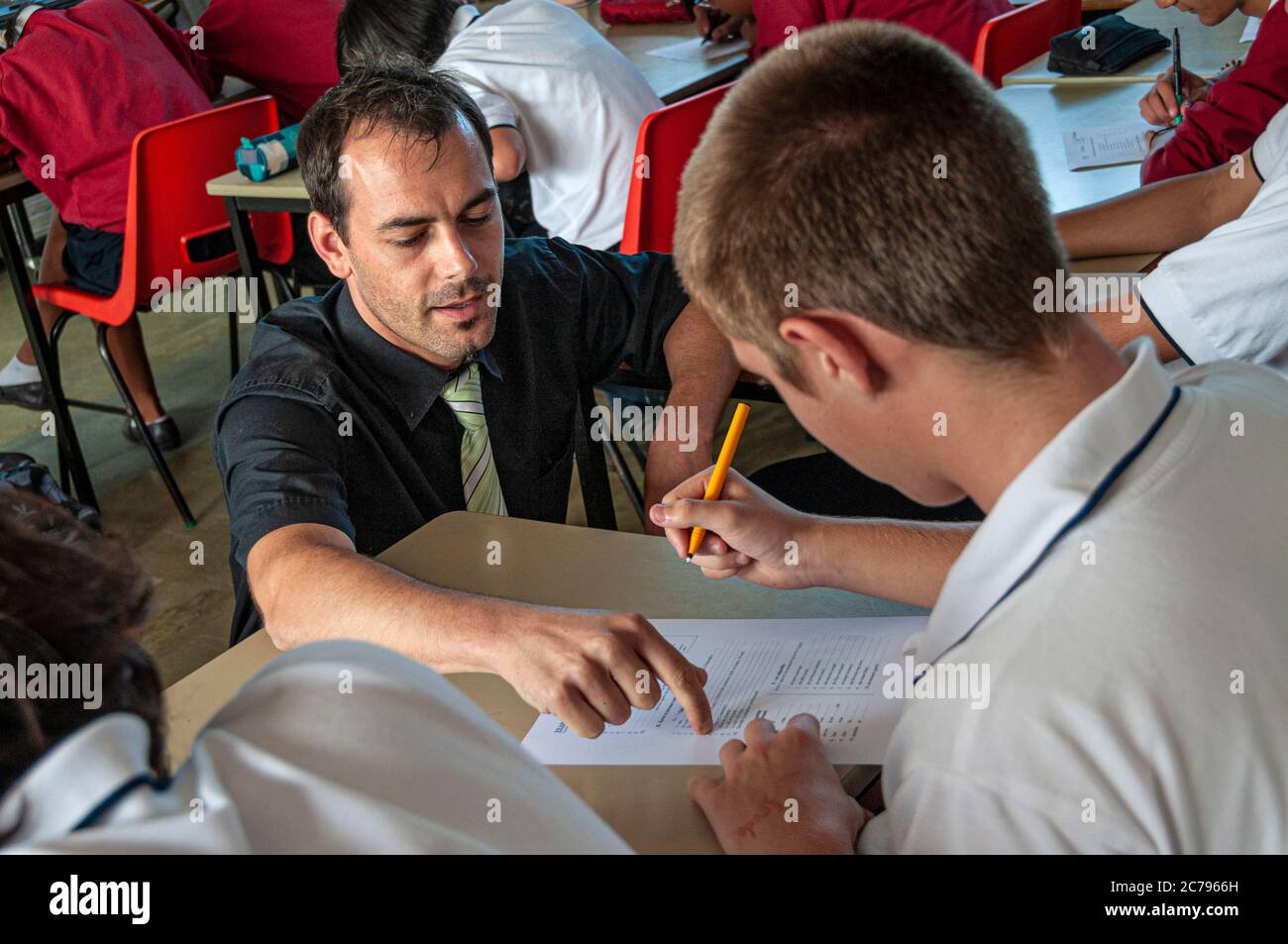 Male teacher coaching one to one a teenage boy student 15-17 years with ...