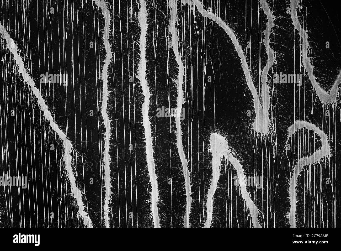 Abstract white paint dribbles splash on a black painted wall, high ...