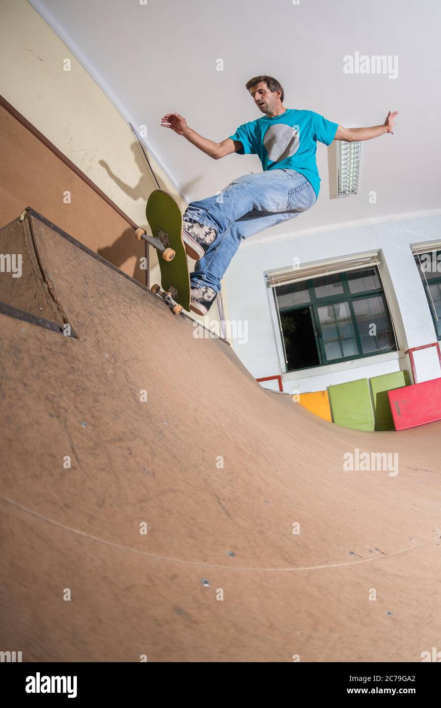 Skateboarder performing a trick on mini ramp at indoor skate park Stock ...
