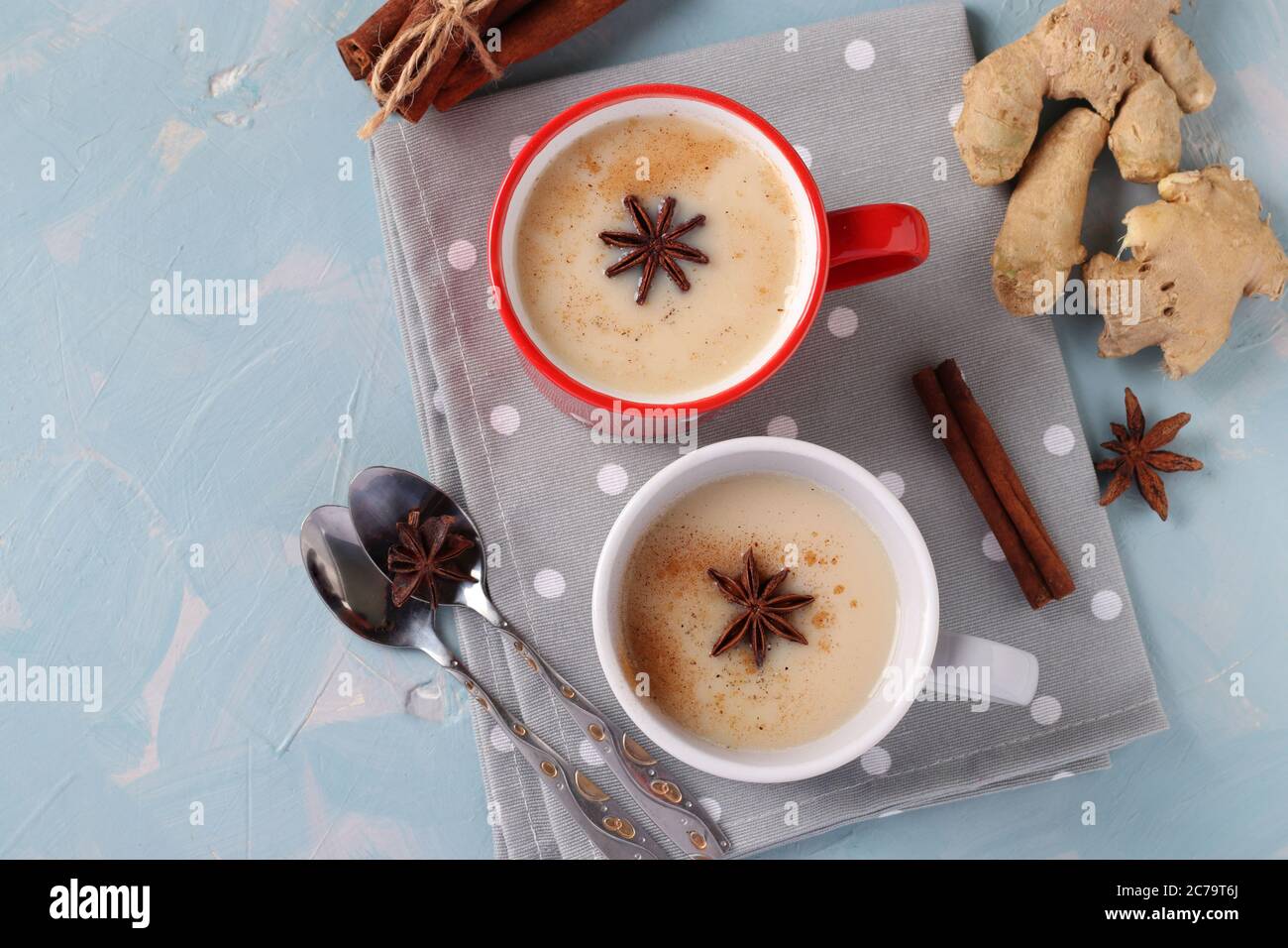 Traditional indian masala tea with spices in two cups on light blue ...