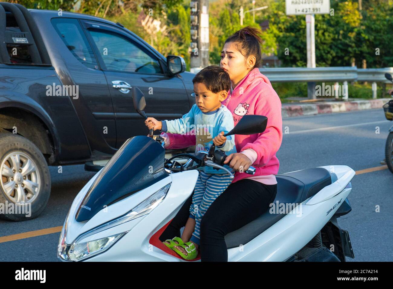 Mom with a small child without helmets rides on a motobike Stock Photo ...