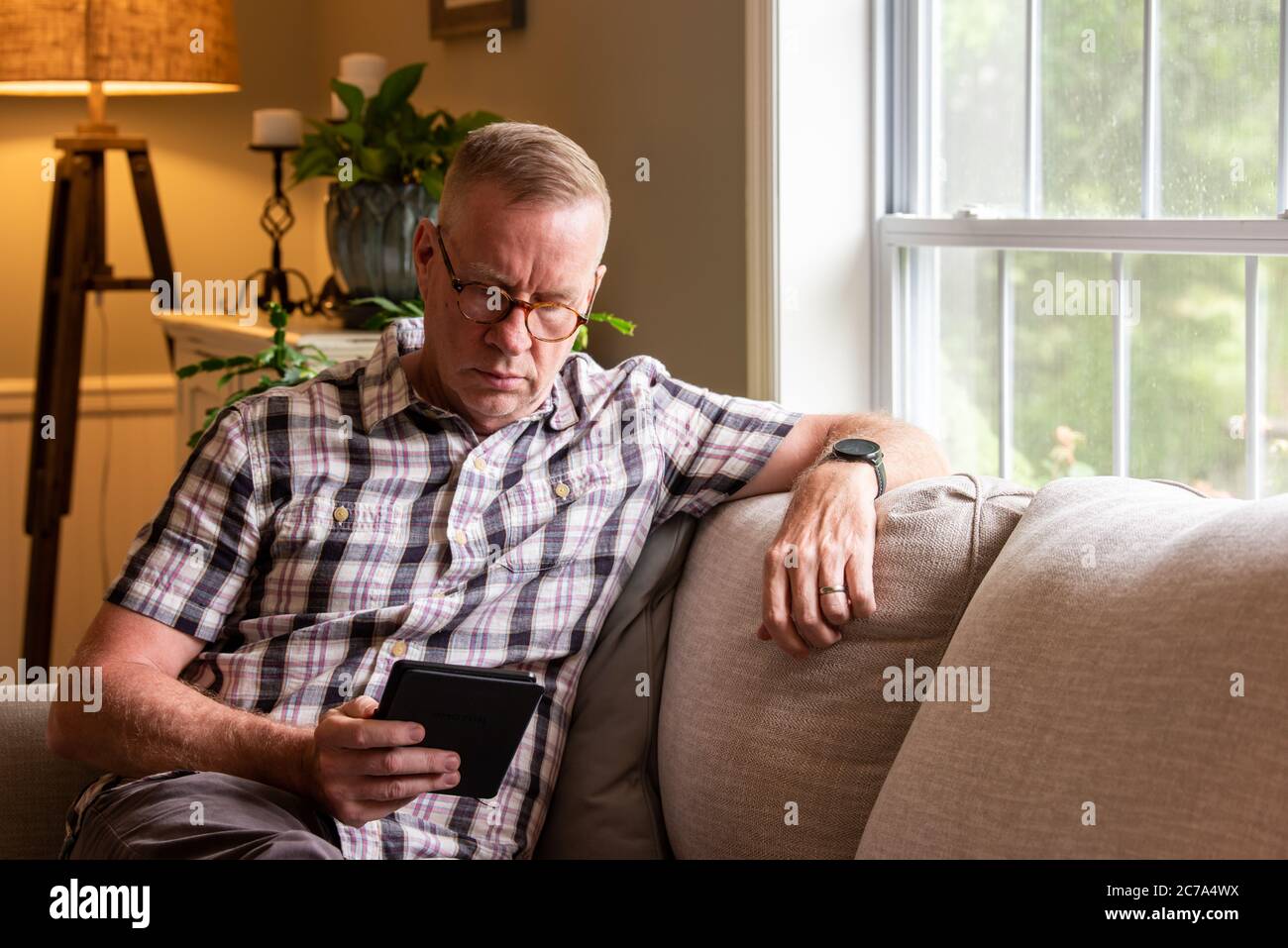 A man sits alone, inside, reading his e-book Stock Photo - Alamy