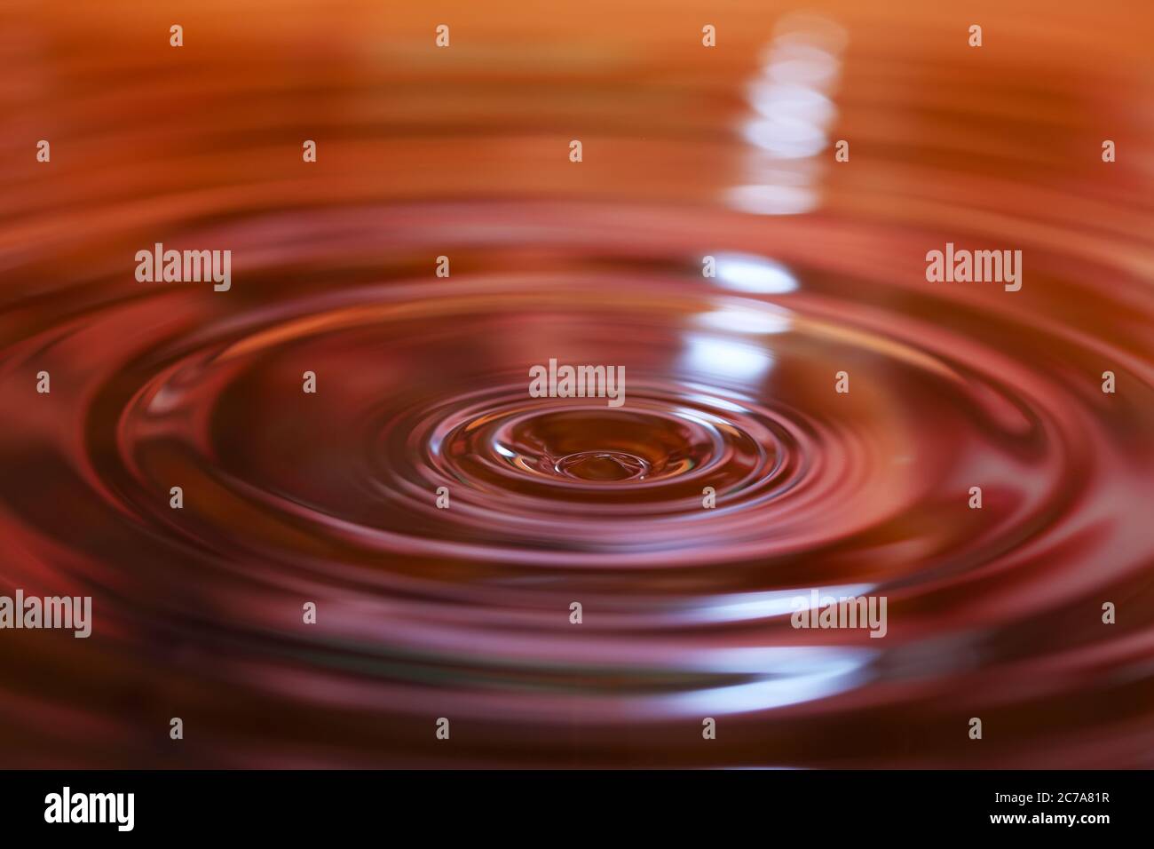 Macro photo of water drops falling into a pool of water, causing a ...