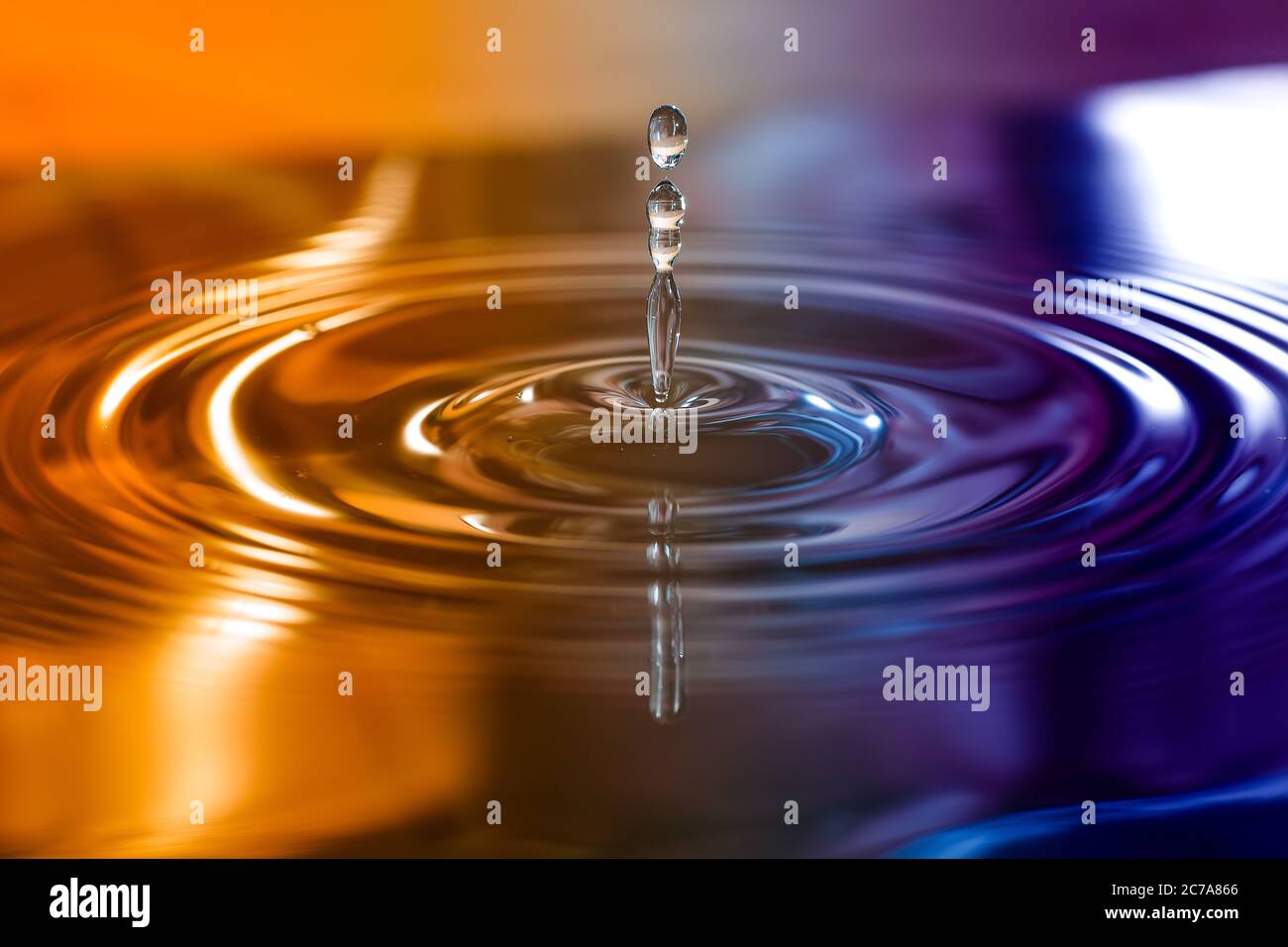 Macro photo of water drops falling into a pool of water, causing a ...