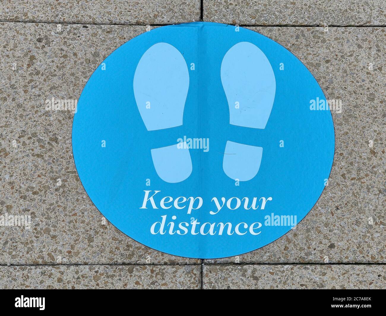 Keep your distance stand here sign on a pavement Stock Photo - Alamy
