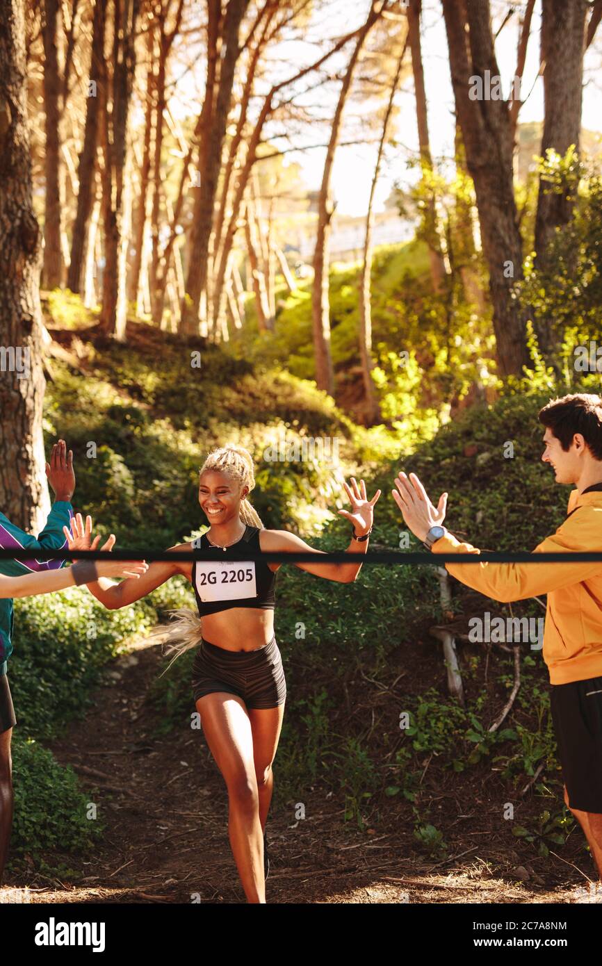 Happy marathon runner being greeted by group of supporter at finish ...