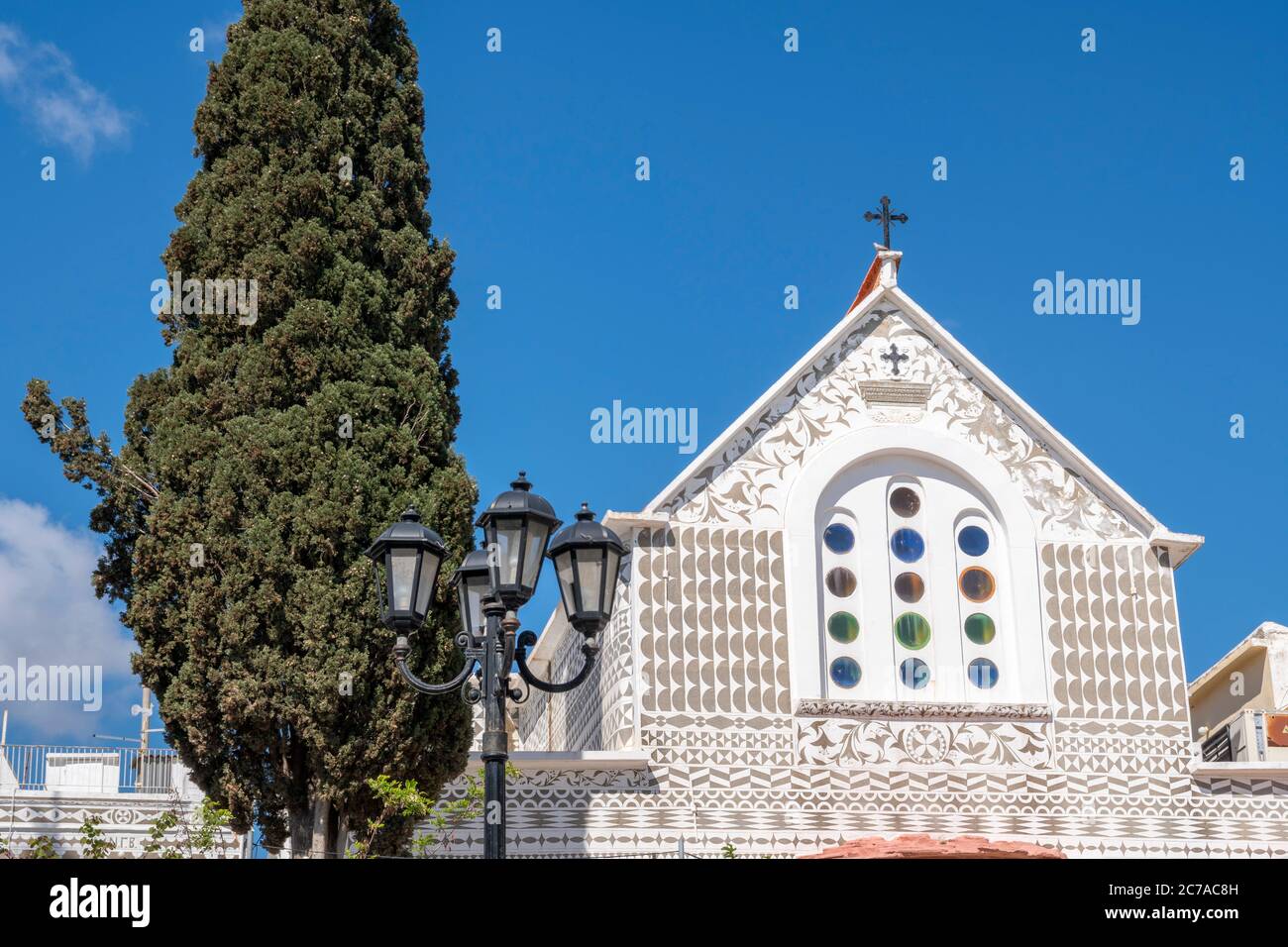 A tree and a white orthodox church with geometric patterns and colored ...